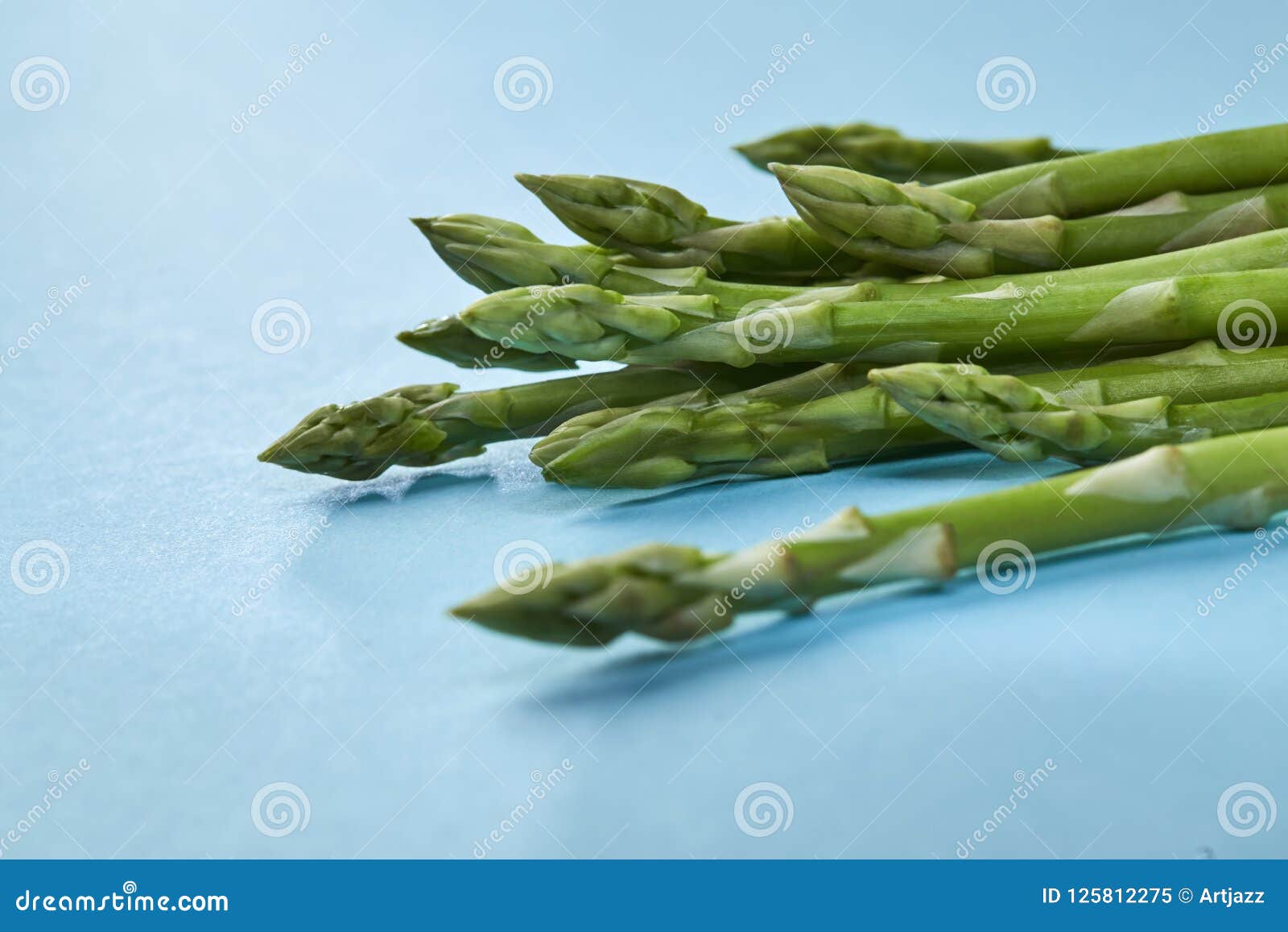 Sprigs of Green Asparagus in a Bunch on a Blue Background for Cooking ... Sprigs of Green Asparagus in a Bunch on a Blue Background for Cooking ...