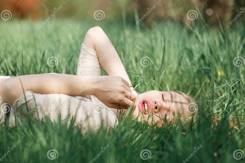 Outdoor Portrait Of Beautiful Blonde Girl Lying On Green Grass Stock
