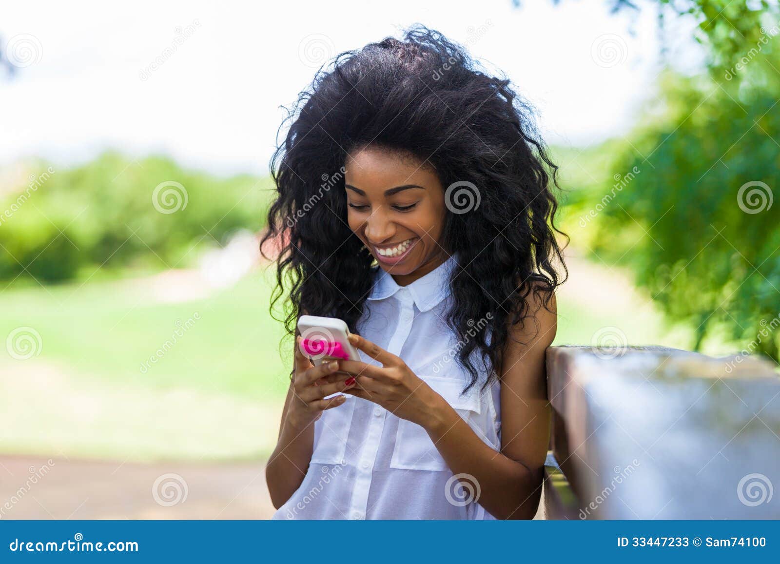 Outdoor Portrait Of A Teenage Black Girl Using A Mobile Phone Stock
