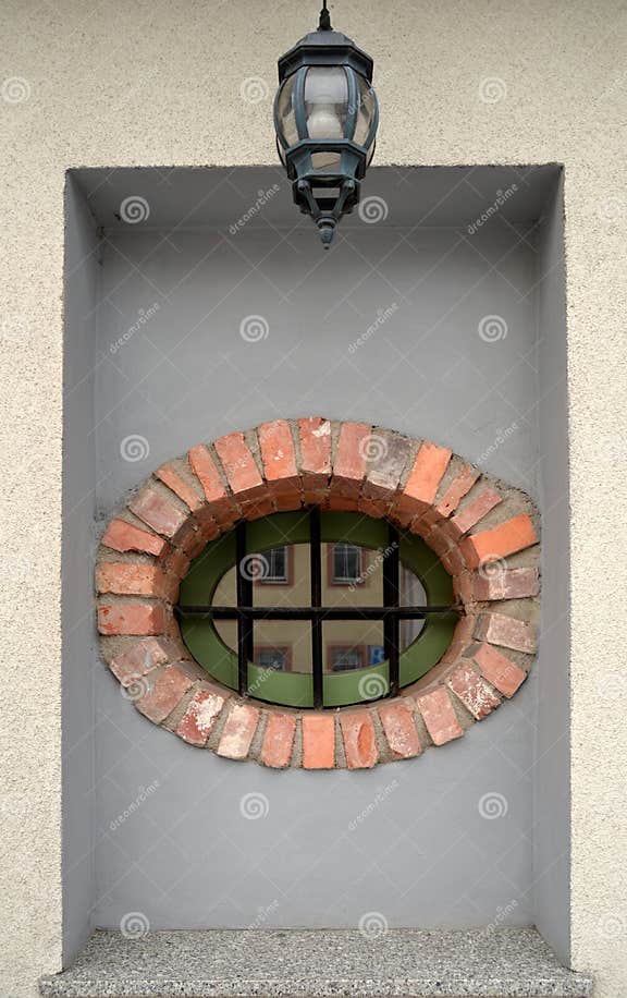 Oval Window Lined with Brick and Grate with Reflection and Lamp Above ...