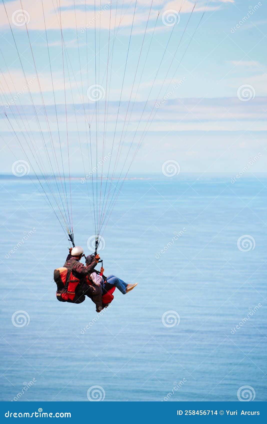 Over the Ocean. Side View of Two Young People Doing Tandem Paragliding ...