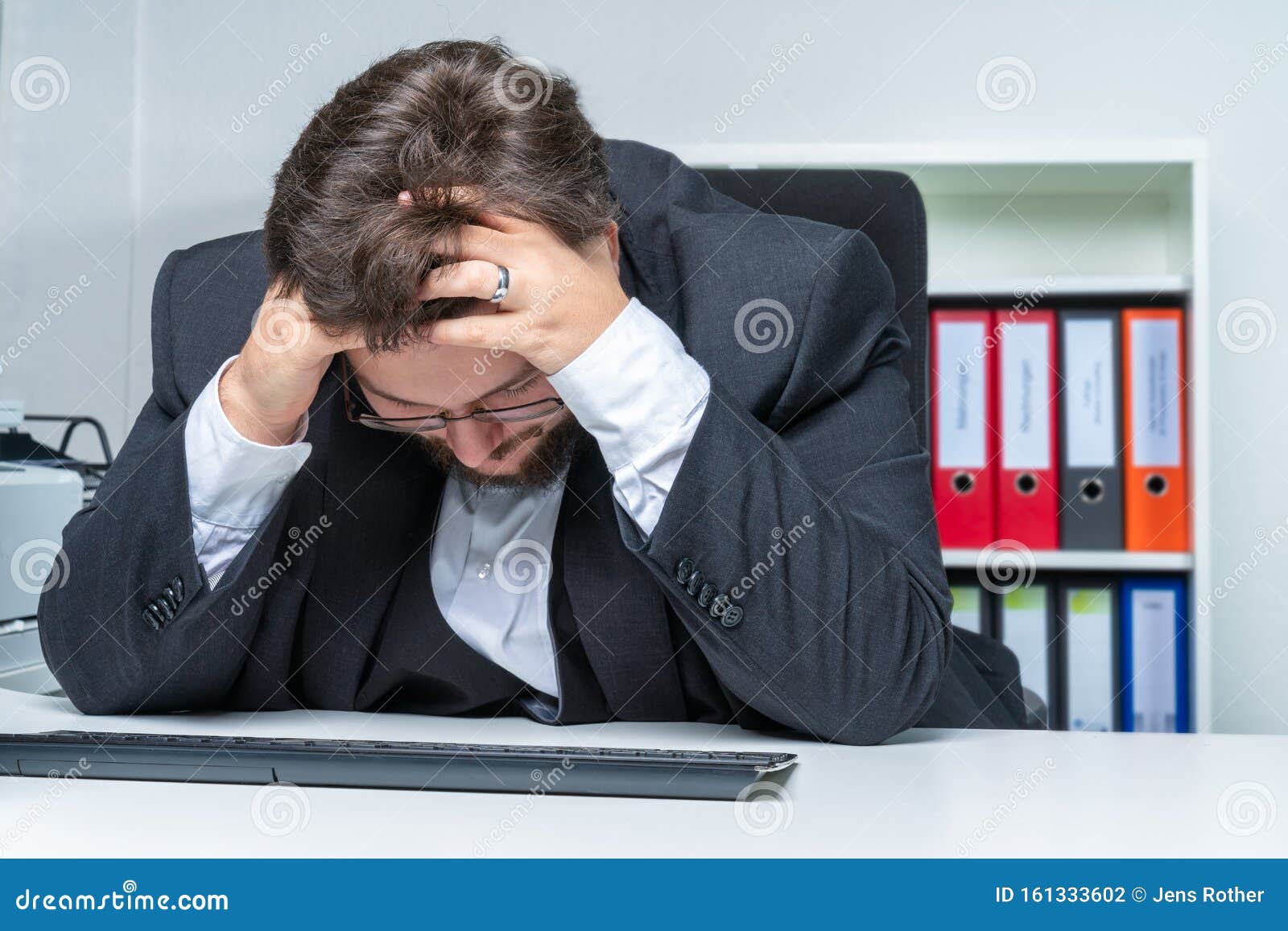 An Over-worked Businessman in the Office Holds His Head Stock Photo ...