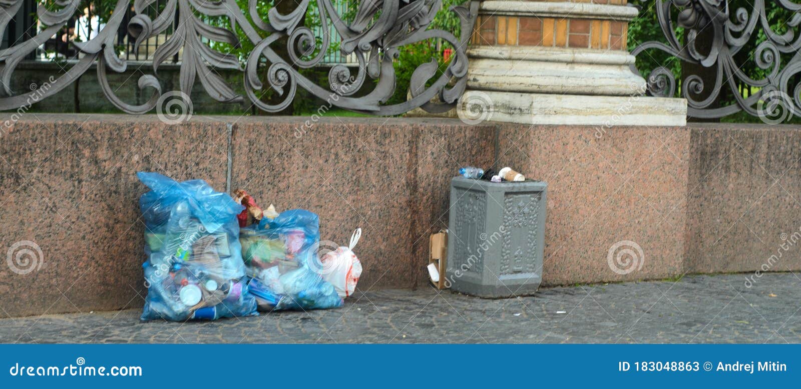 Overflowing Trash Can and Three Full Garbage Bags at the Fence of the ...
