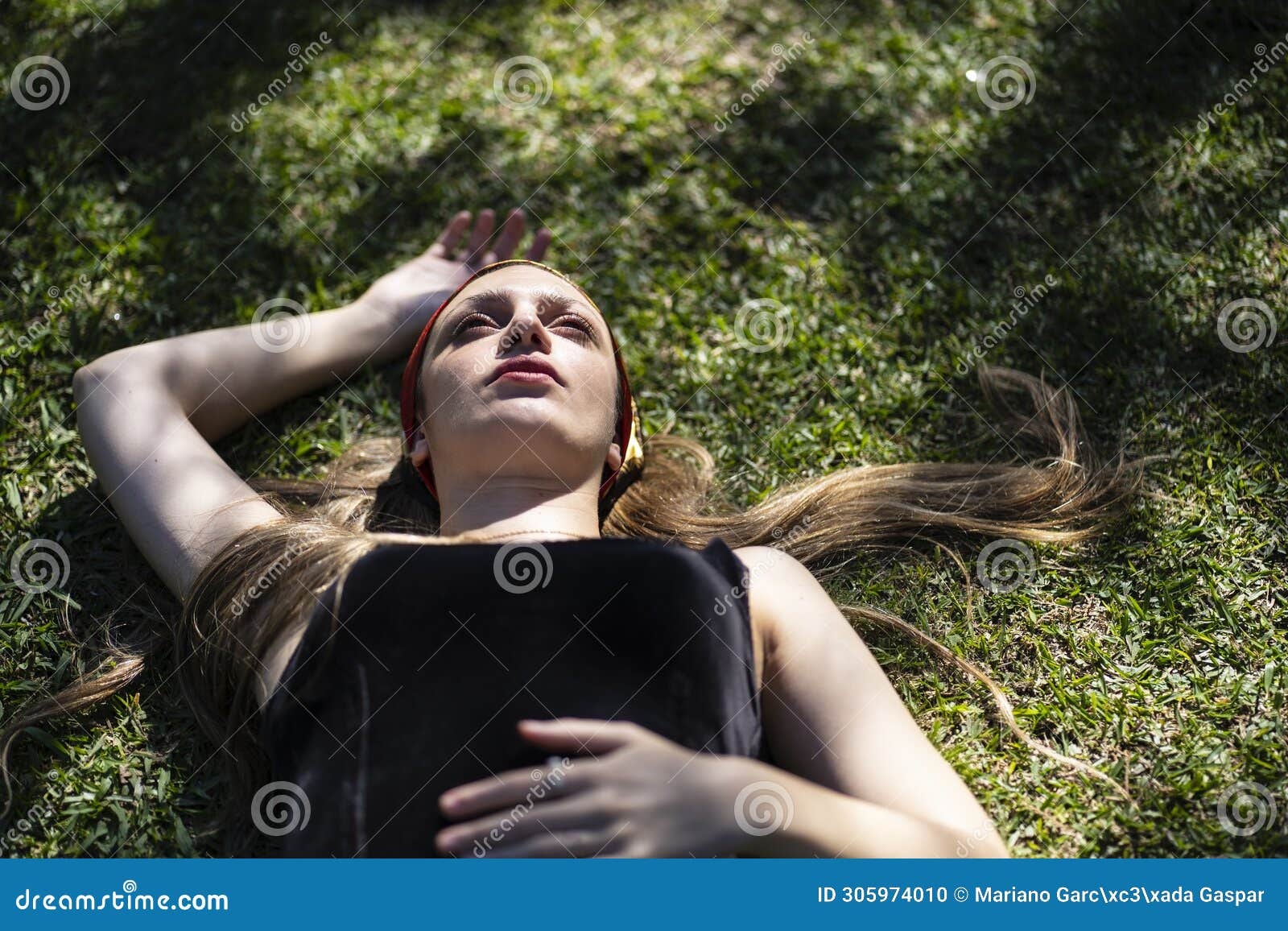 Overhead Portrait Of Blonde Woman Lying On The Grass With Lights And