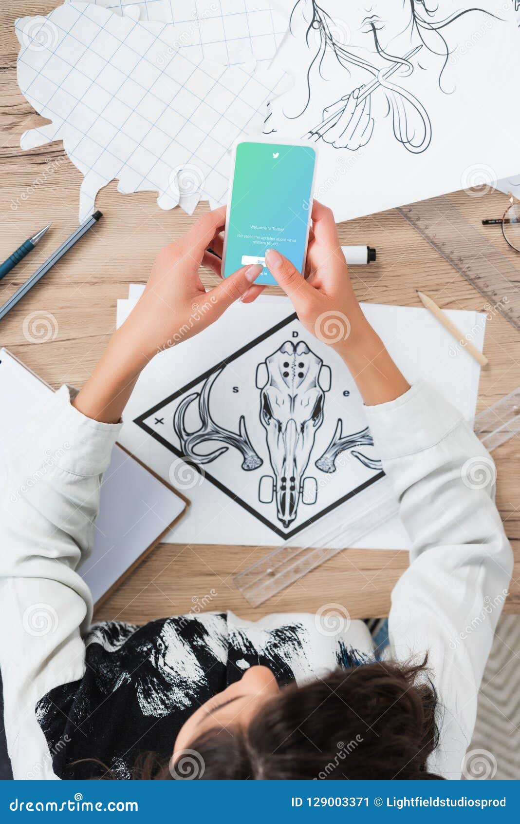 Overhead View of Female Designer Using Smartphone with Twitter ...