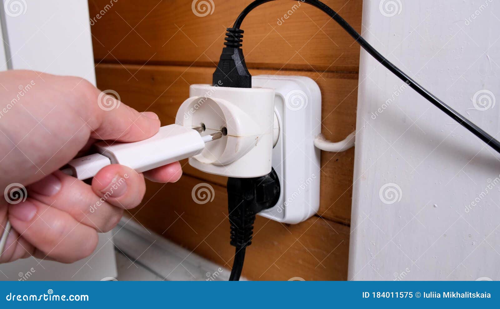 Overloaded Outlet with an Extension and Many Sockets Plugged in, a Hand ...