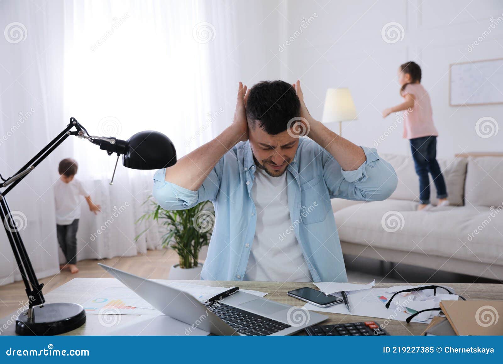 Overwhelmed Man Combining Parenting and Work at Home Stock Image ...