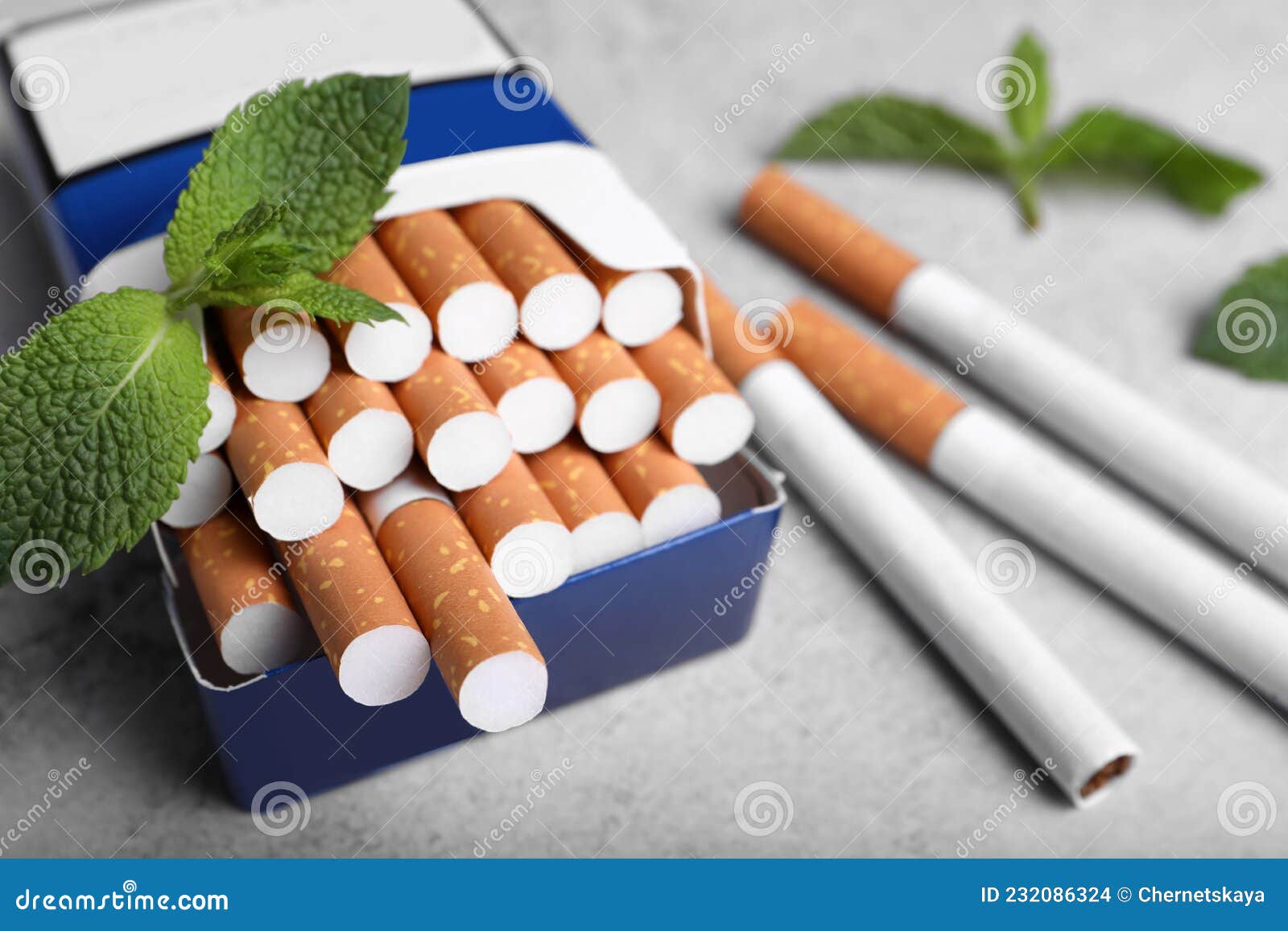 Pack of Menthol Cigarettes and Mint Leaves on Grey Table, Closeup Stock ...