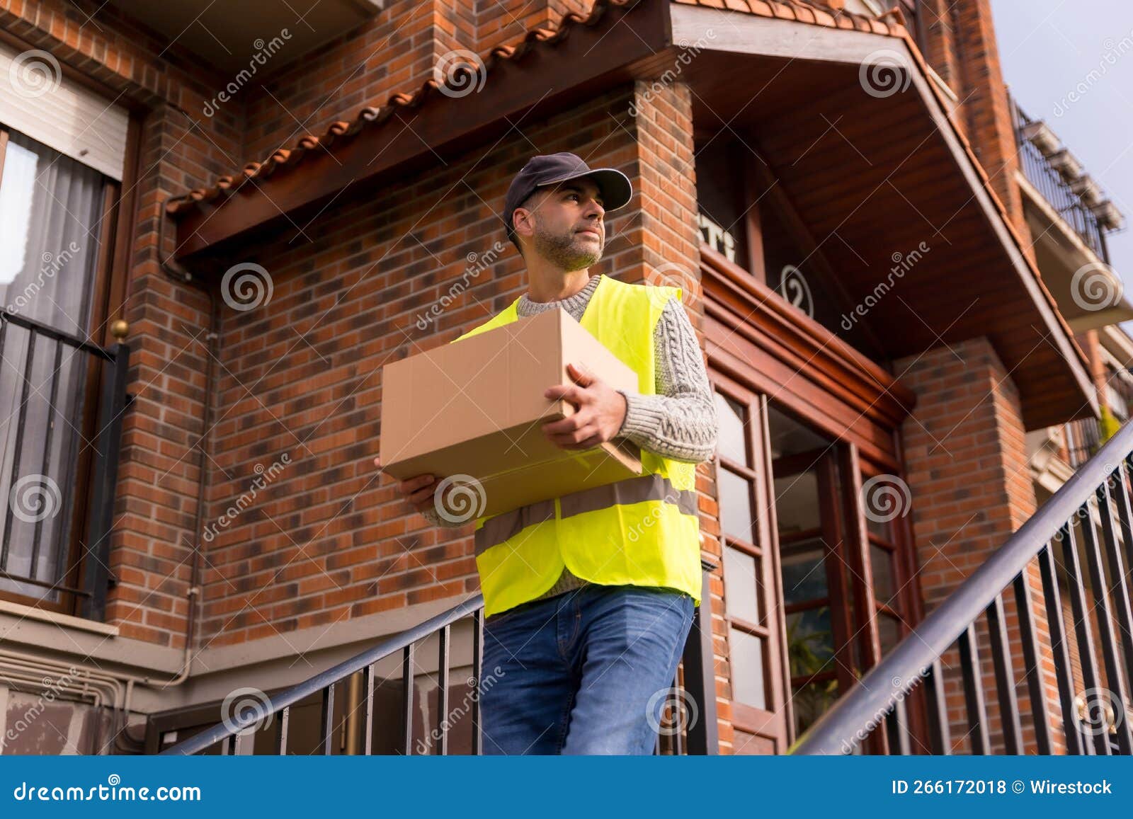 Package Delivery Carrier with a Box from an Online Store in Front of a ...