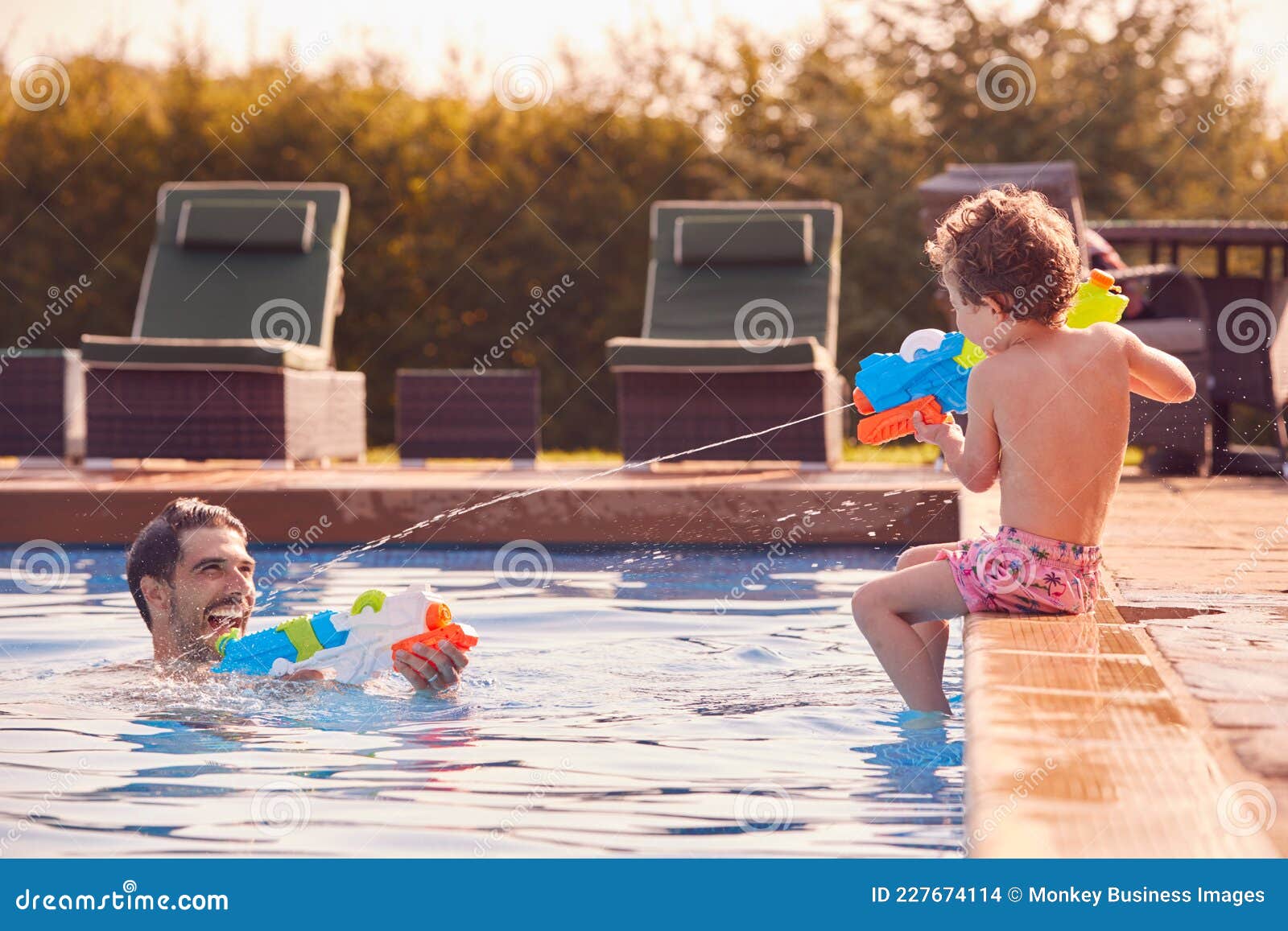 Pai E Filho Se Esgueirando Com Pistolas De água Jogando Na Piscina Nas