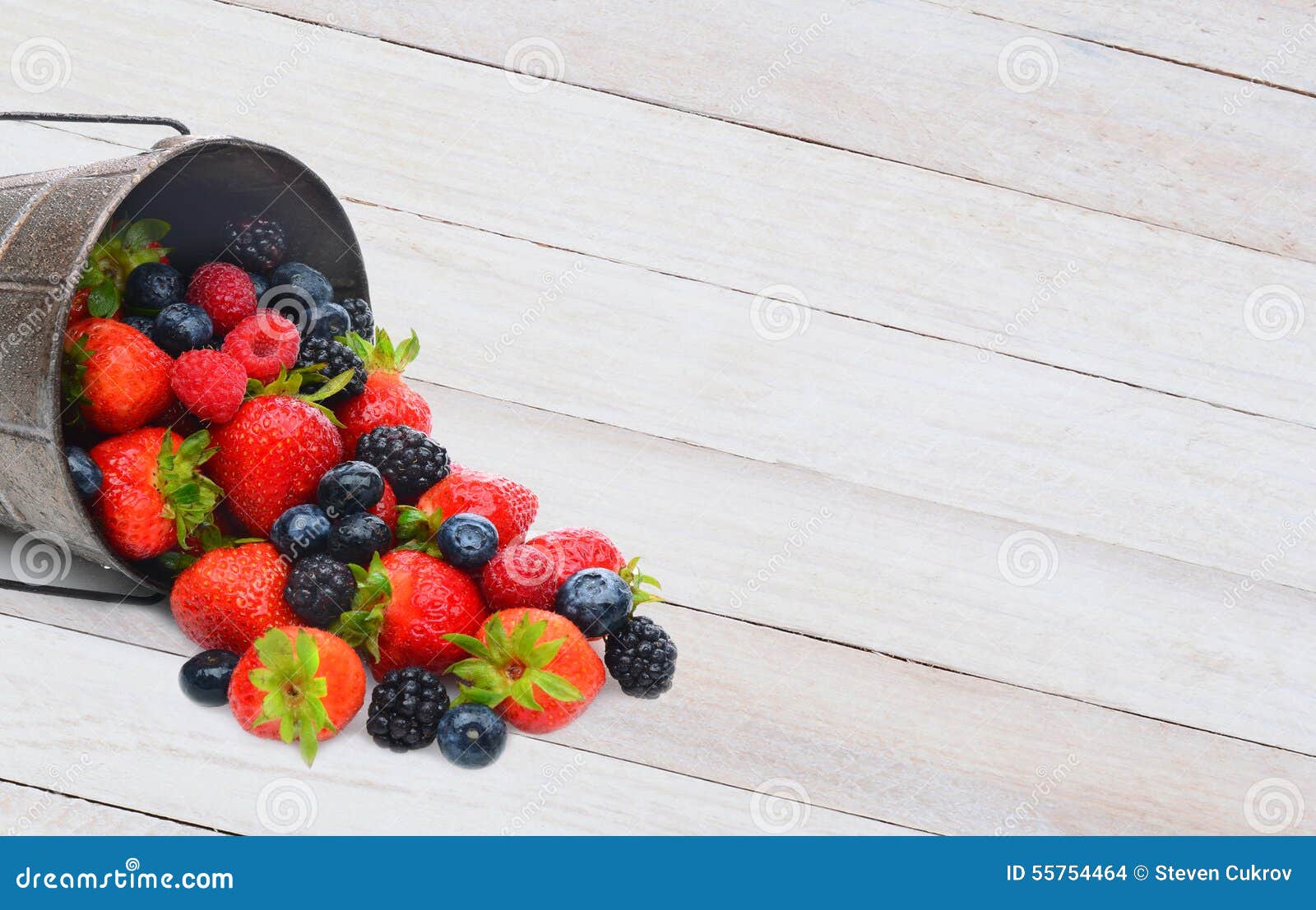 Pail with Berries Spilling on Wood Table Stock Photo - Image of black ...