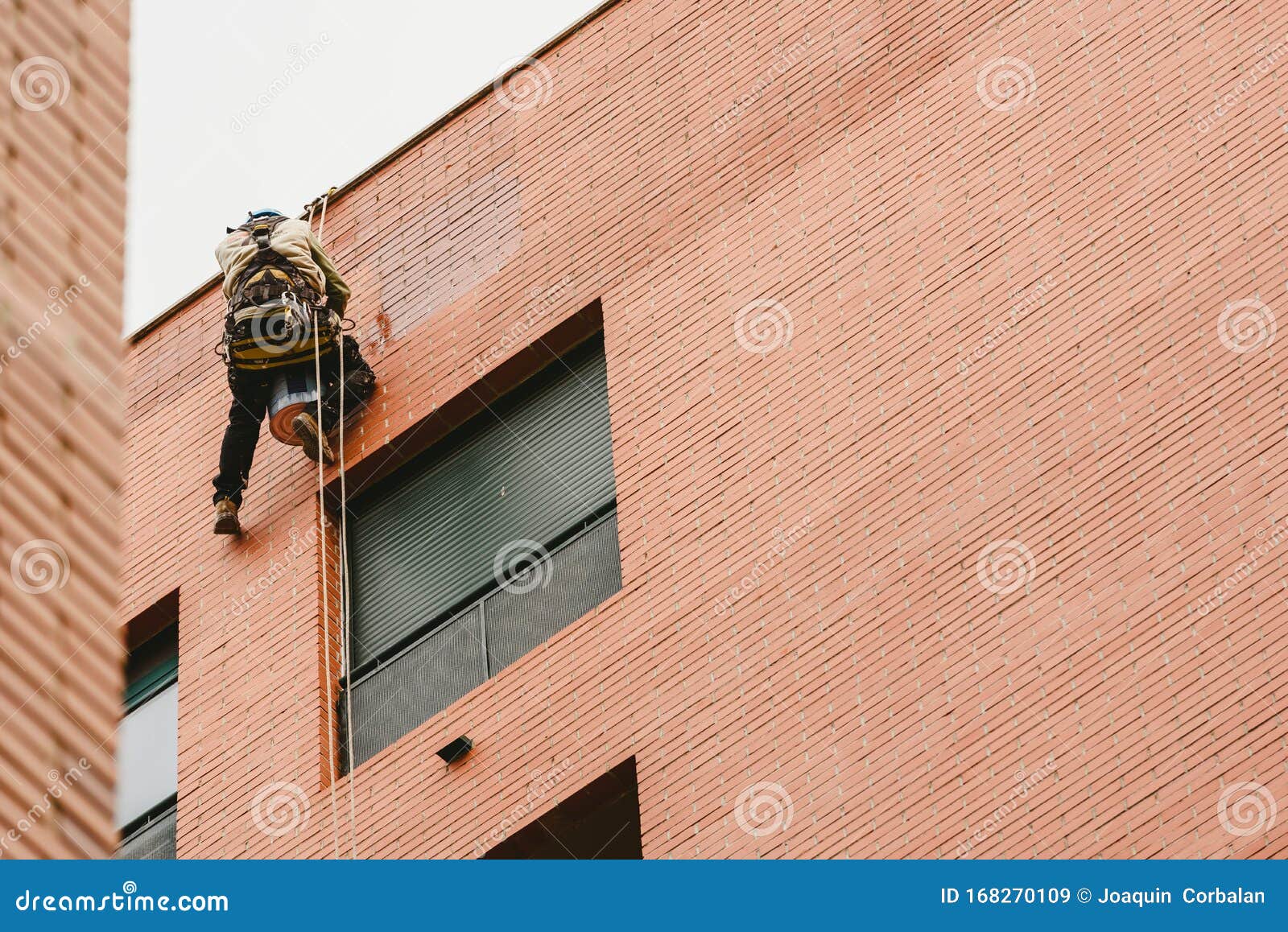 Painter Perched Hanging on the Walls of a Building with Ropes Stock ...