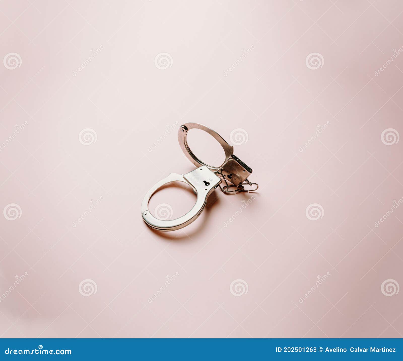 A Pair of Metallic Handcuffs Over a Flat and Bright Pastel Pink ...