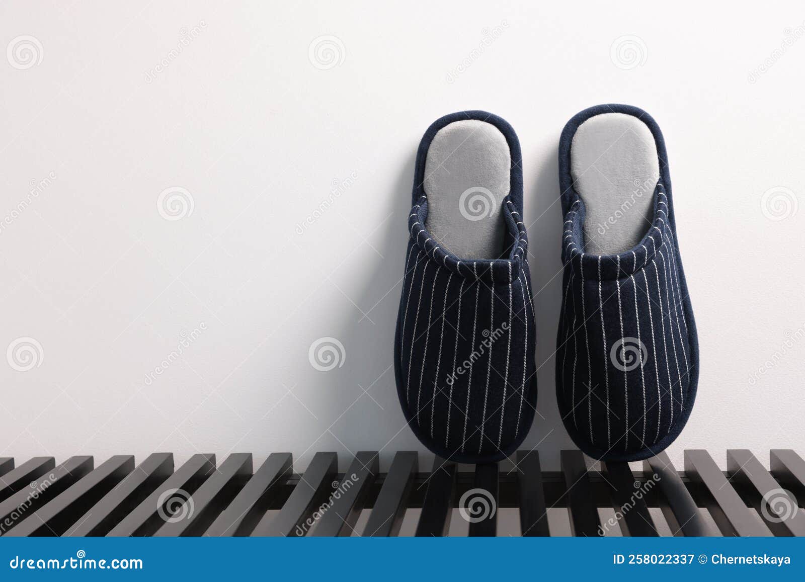 Pair of Stylish Slippers on Bench Against Light Grey Background, Space ...