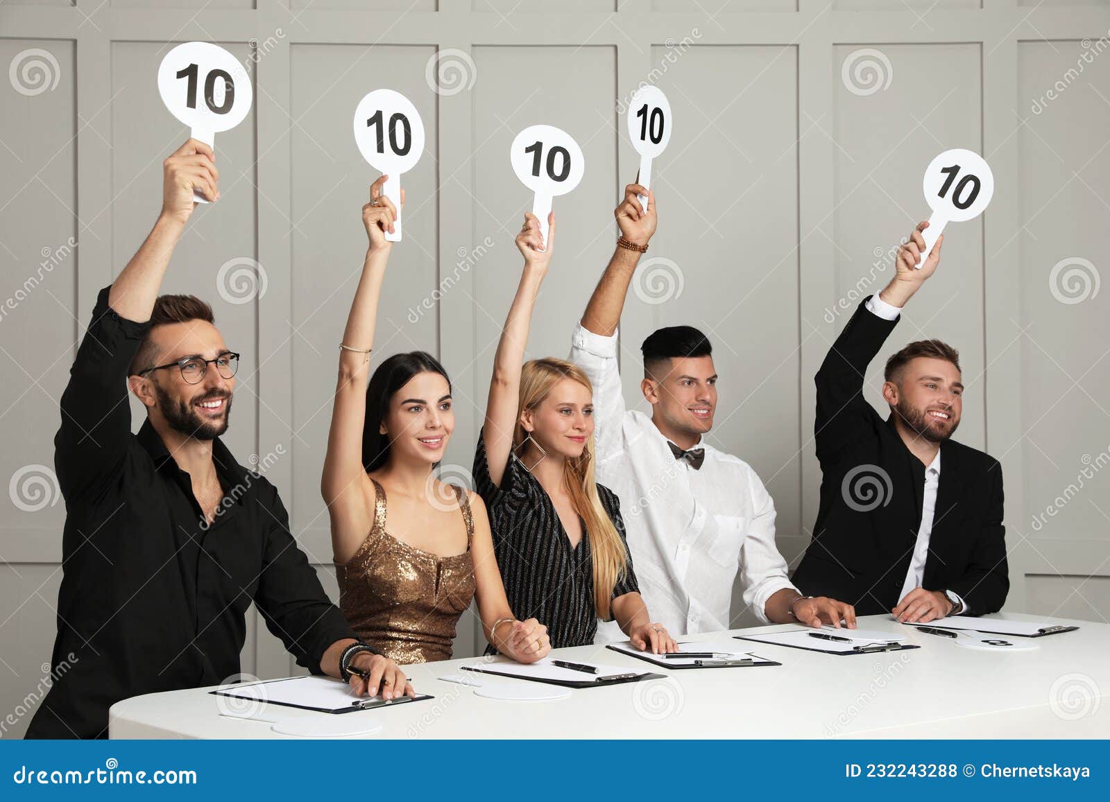 Panel of Judges Holding Signs with Highest Score at Table Against Light ...