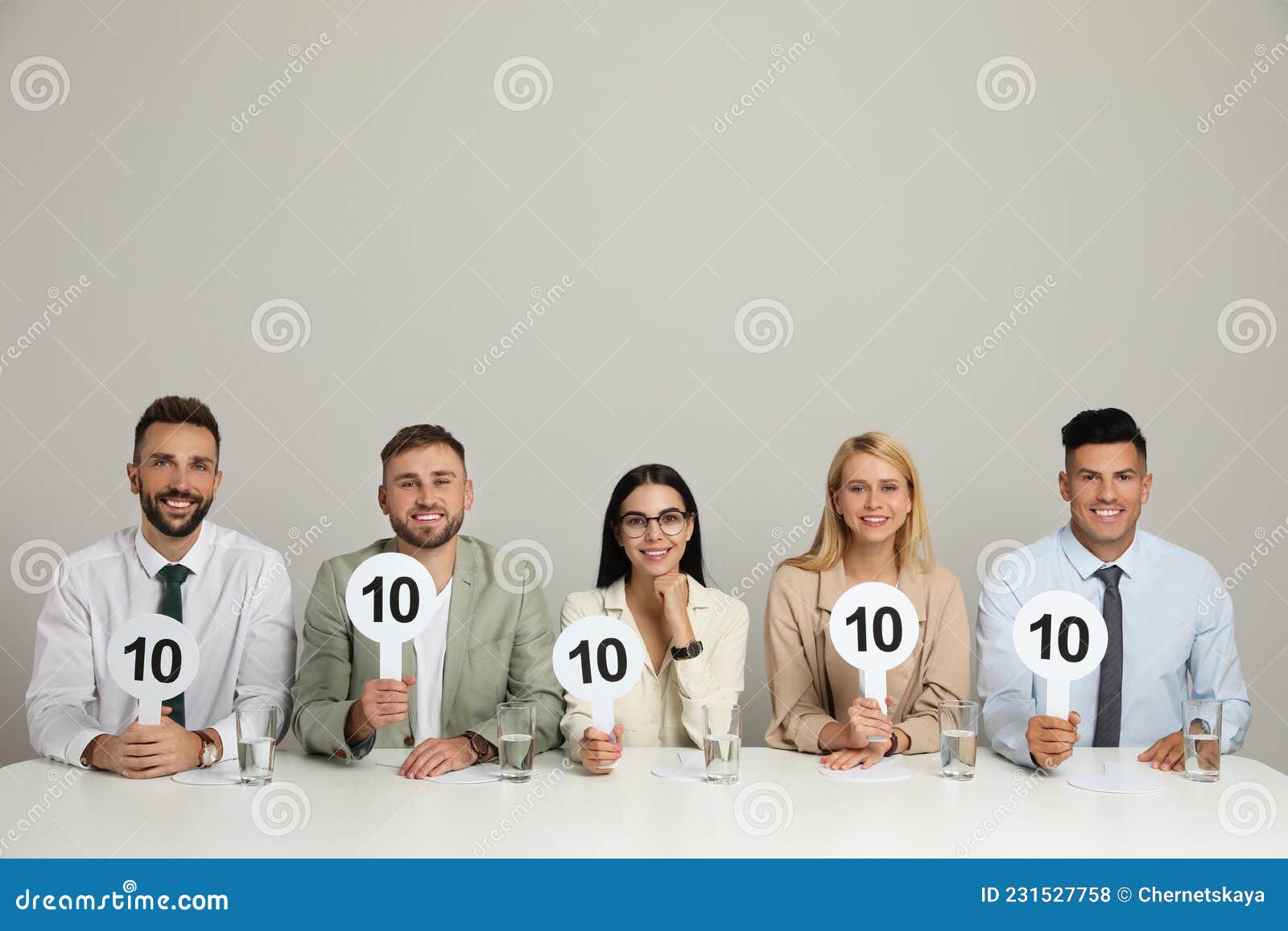 Panel of Judges Holding Signs with Highest Score at Table on Beige ...