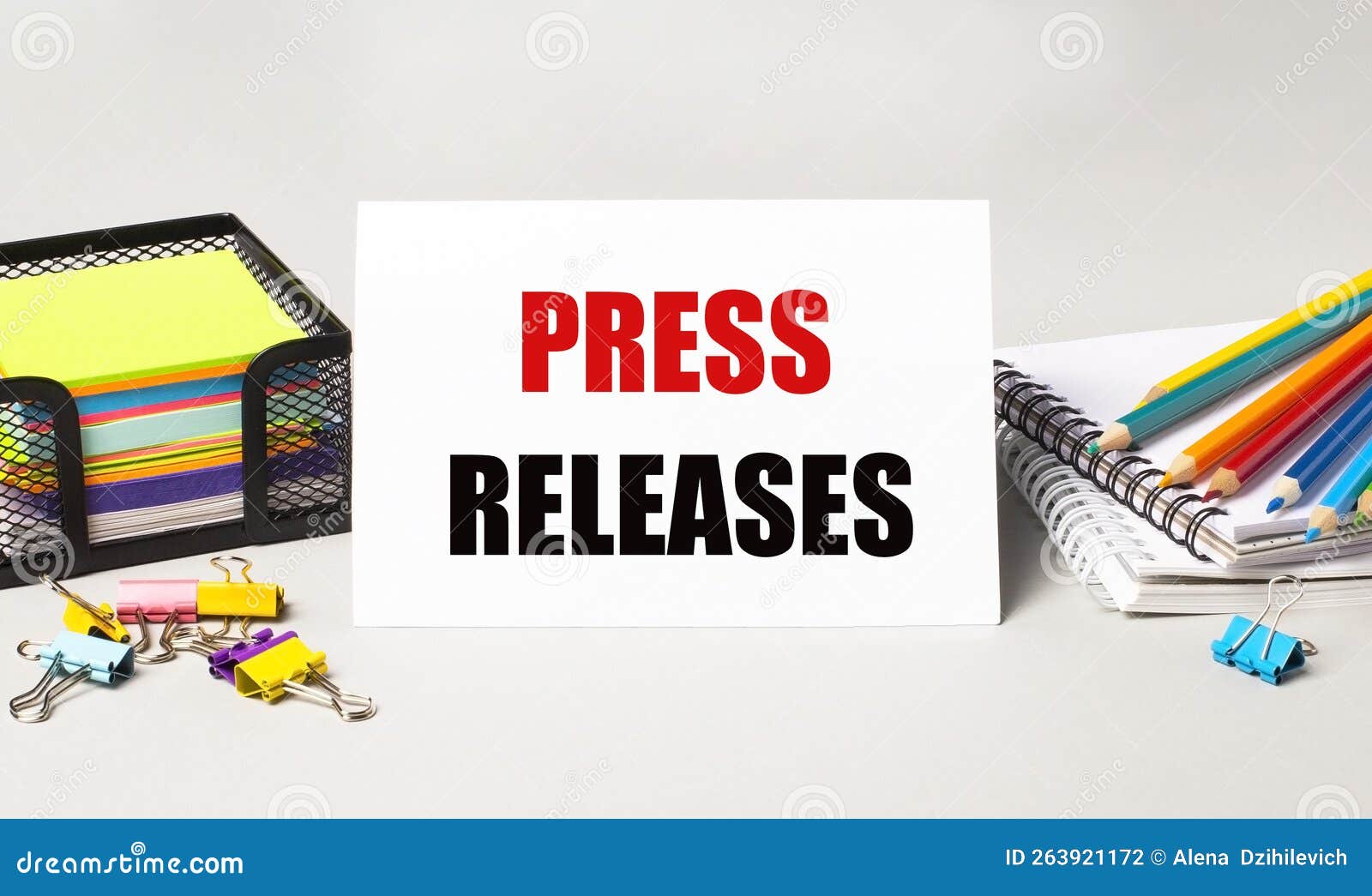 A Paper Card with the Text PRESS RELEASES, Multi-colored Pencils ...