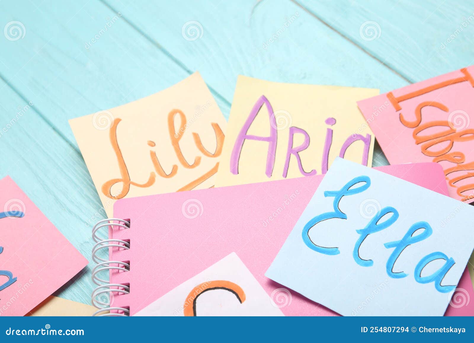 Paper Notes with Different Baby Names and Notebook on Light Blue Wooden ...