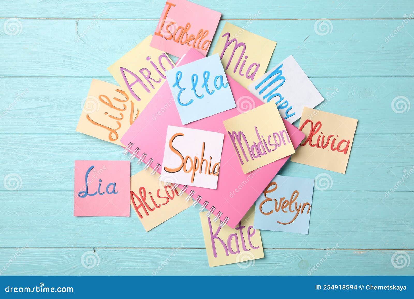 Paper Notes with Different Baby Names and Notebook on Blue Wooden Table ...
