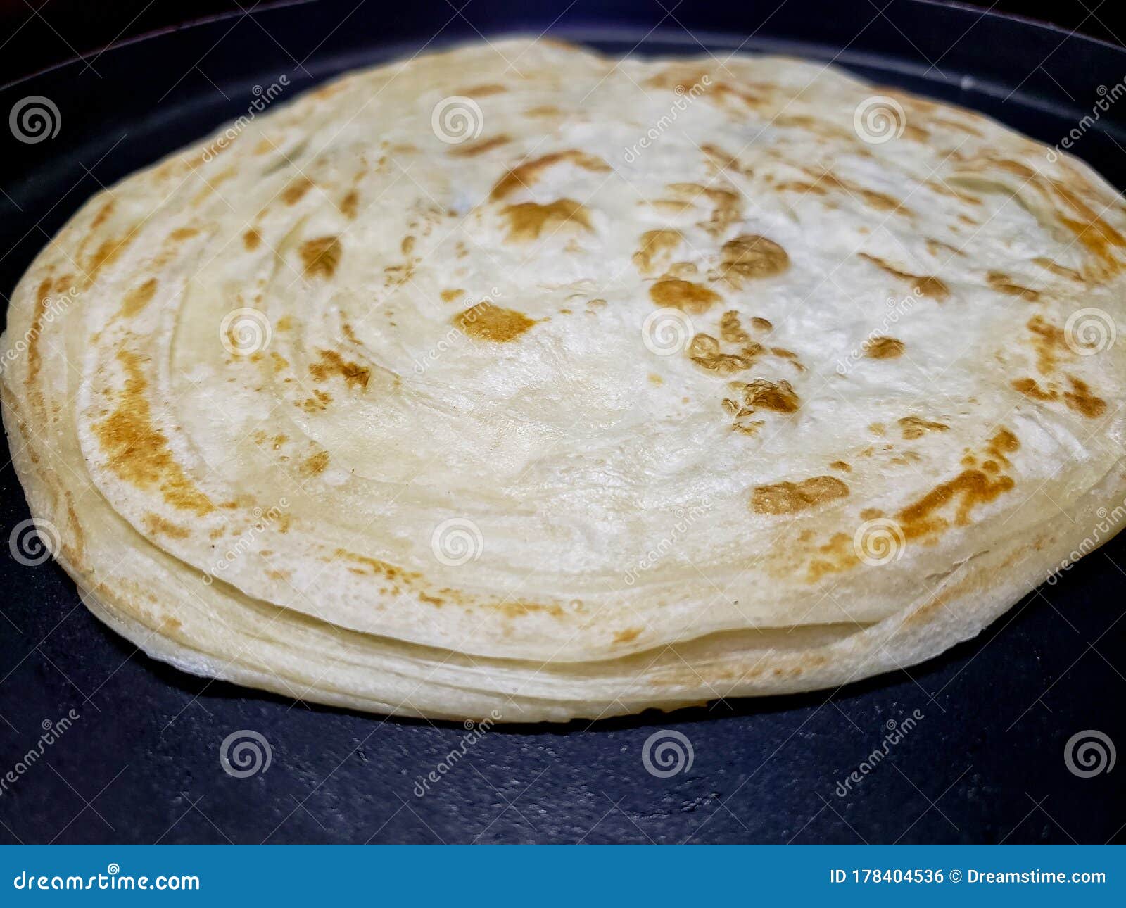 Paratha on the frying pan stock photo. Image of flower - 178404536