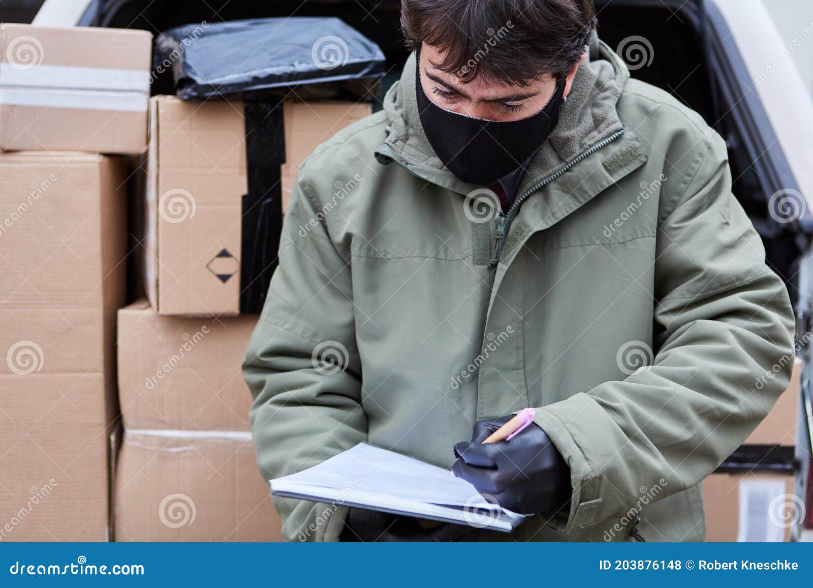 Parcel Delivery Man with Face Mask Checks Deliveries in Front of the ...