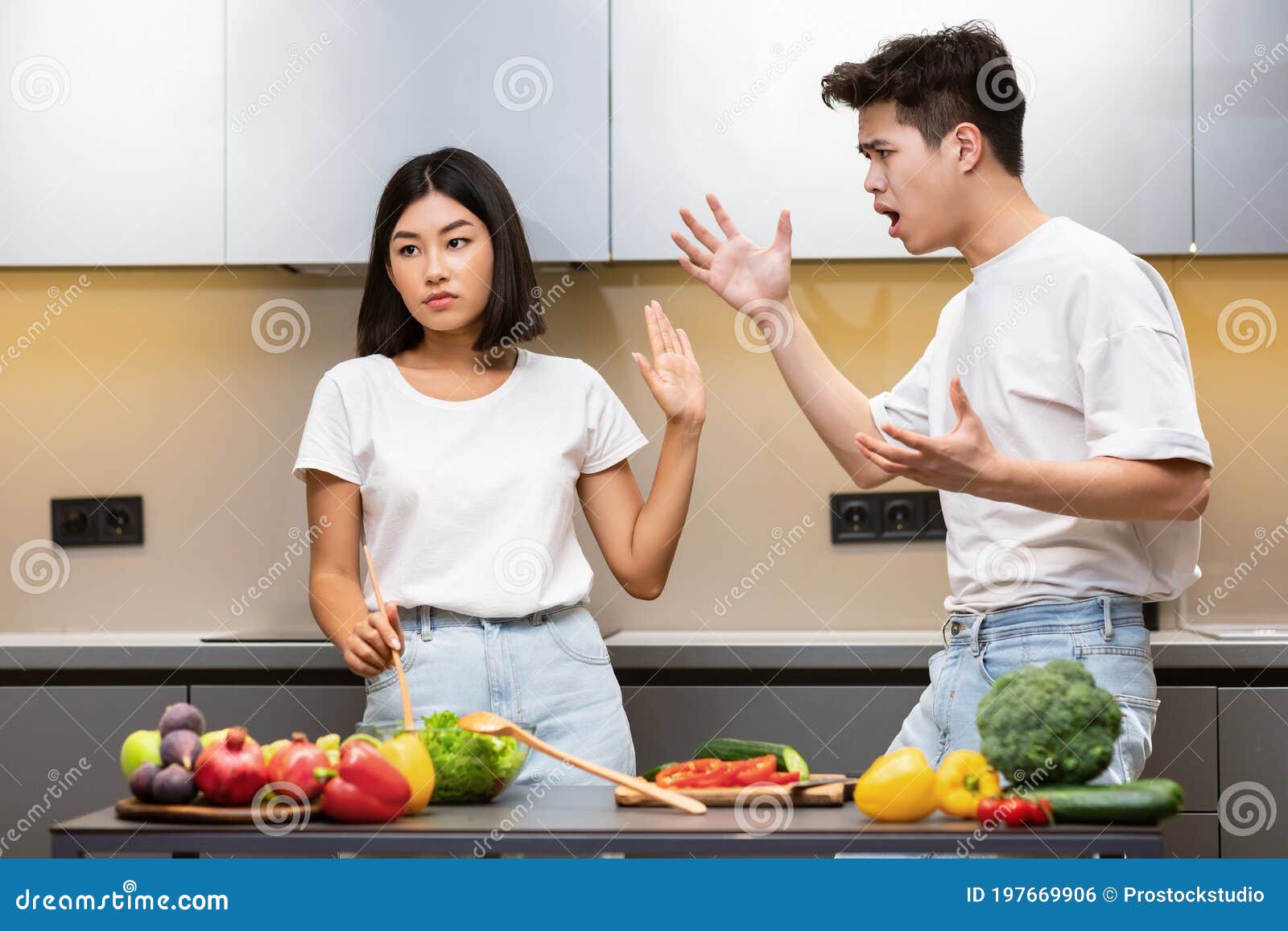 Pareja Familiar Con Quarrel Preparando La Cena De Pie En Cocina ... Pareja Familiar Con Quarrel Preparando La Cena De Pie En Cocina ...