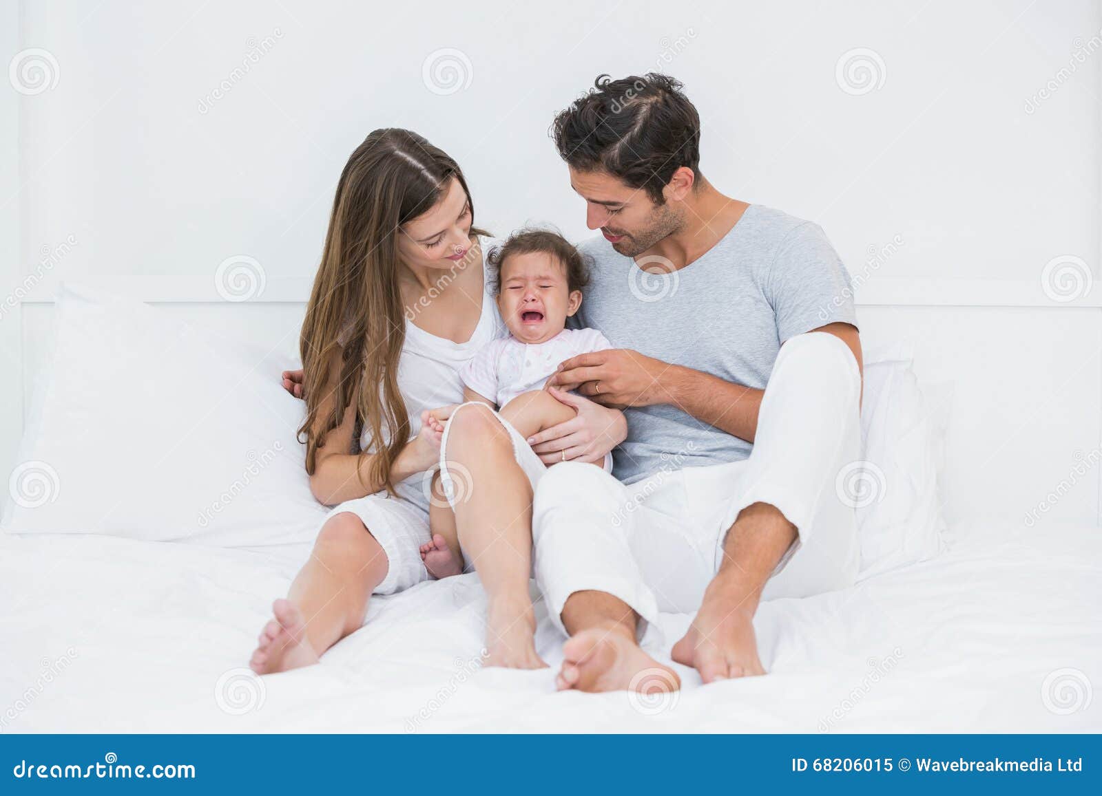 Parents with Crying Baby Sitting on Bed Stock Image - Image of daughter ...
