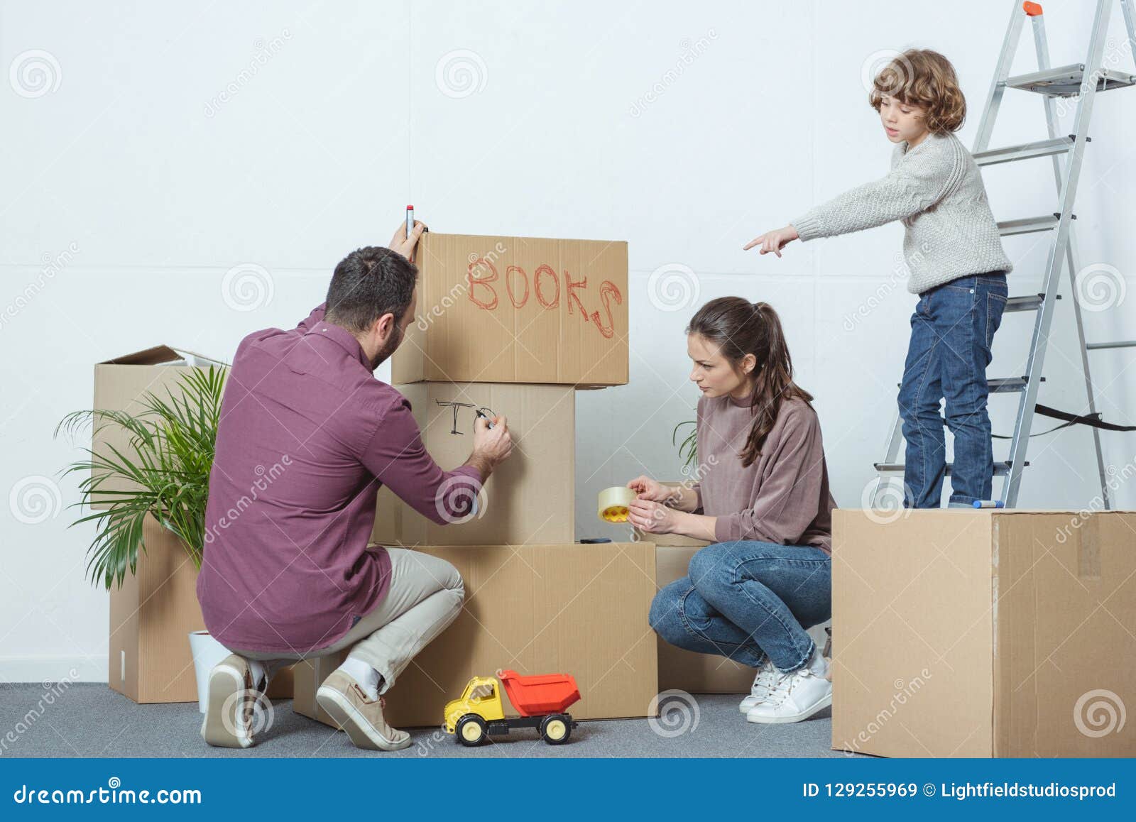 Parents Packing Boxes and Son Pointing with Finger Stock Image - Image ...