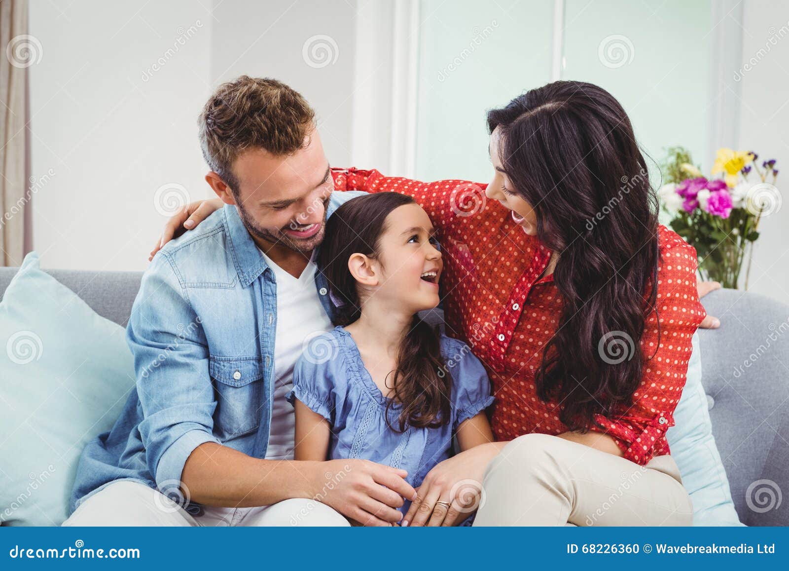 Parents Smiling while Sitting with Daughter on Sofa Stock Photo - Image ...