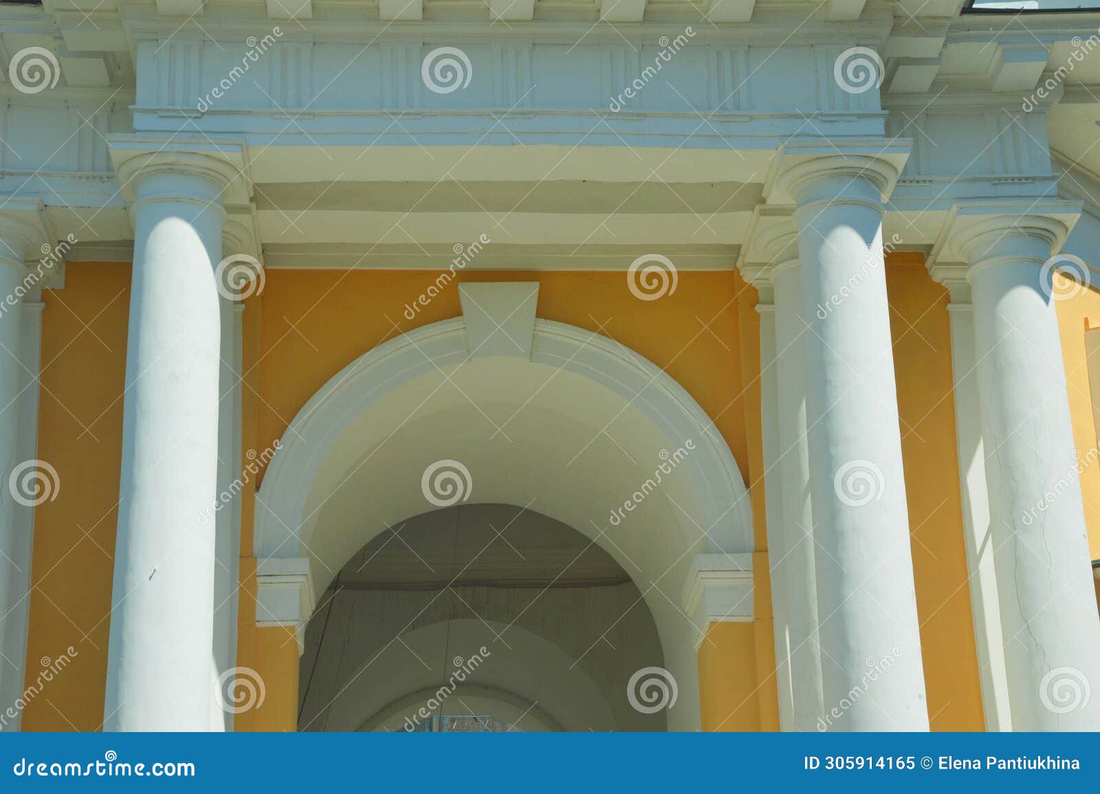 Part of the Facade of an Old House with Yellow Arches and White Columns ...