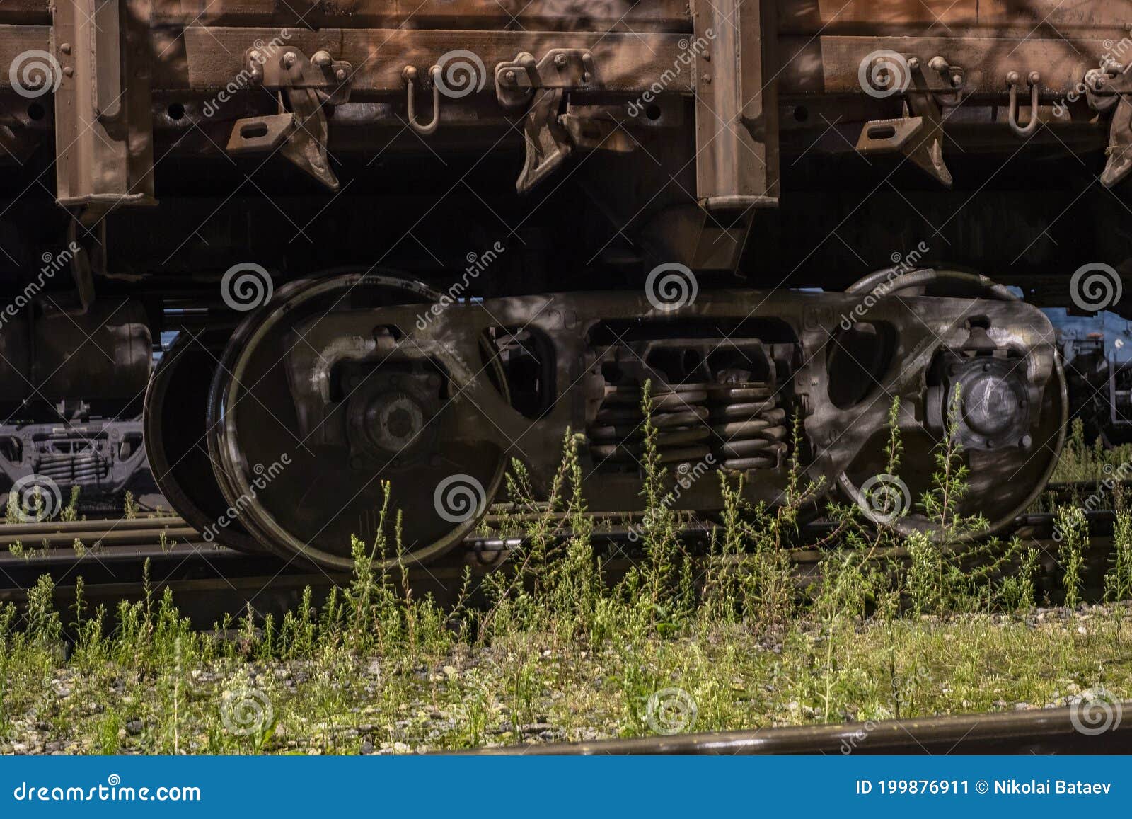 A Freight Railroad Car Stands Behind Bushes And A Metal Fence Royalty ...