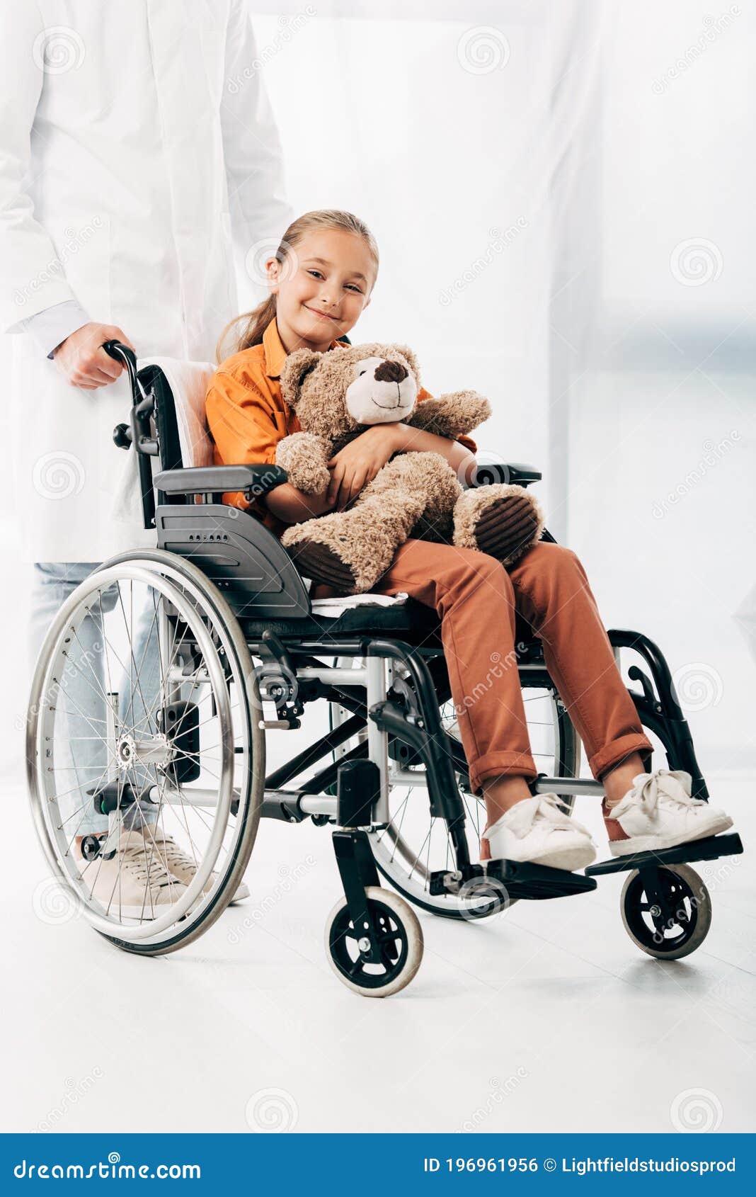 View of Pediatrist in White Coat and Kid with Teddy Bear on Wheelchair ... View of Pediatrist in White Coat and Kid with Teddy Bear on Wheelchair ...
