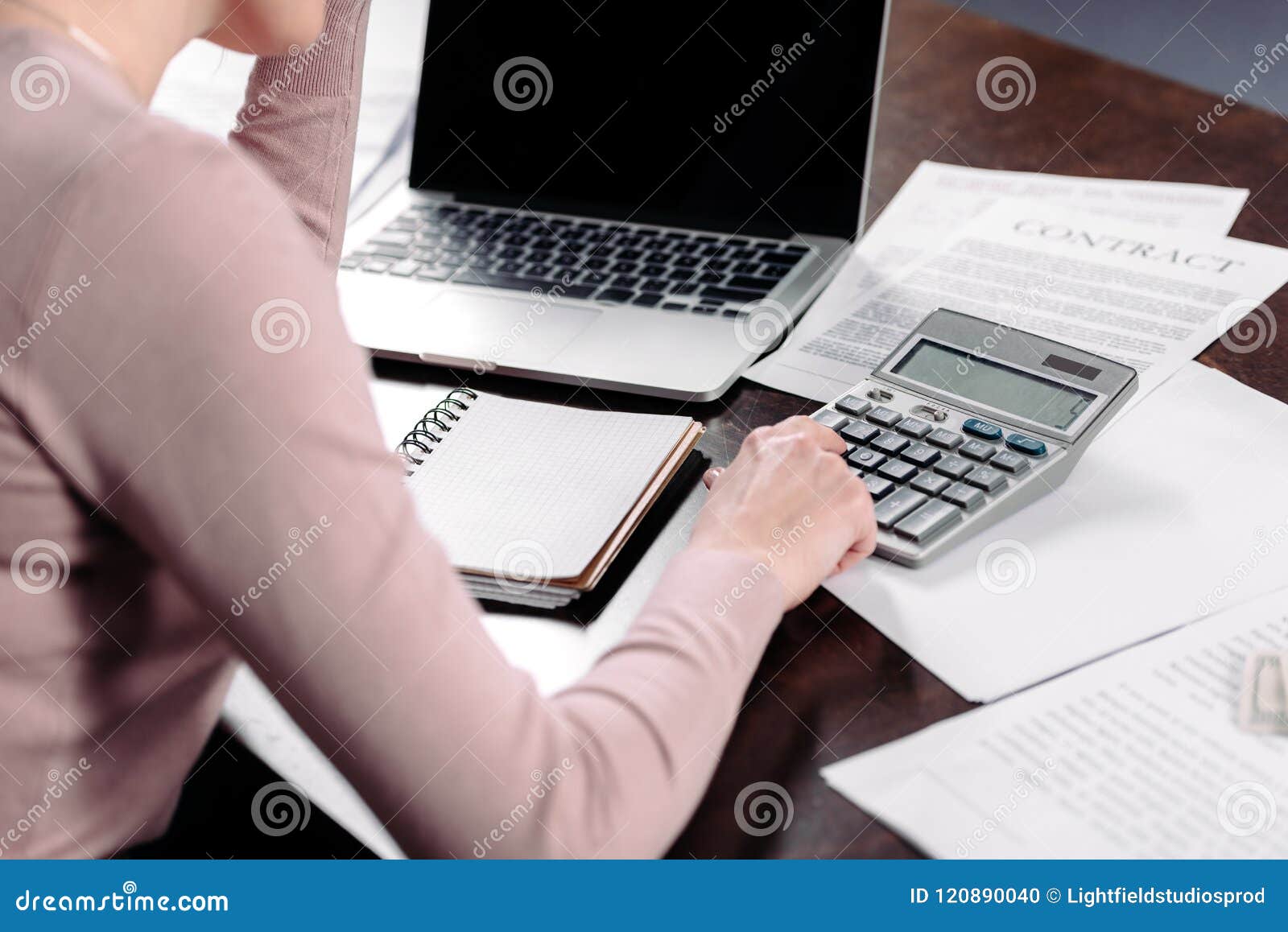 Partial View of Woman Making Calculations at Table with Laptop and ...