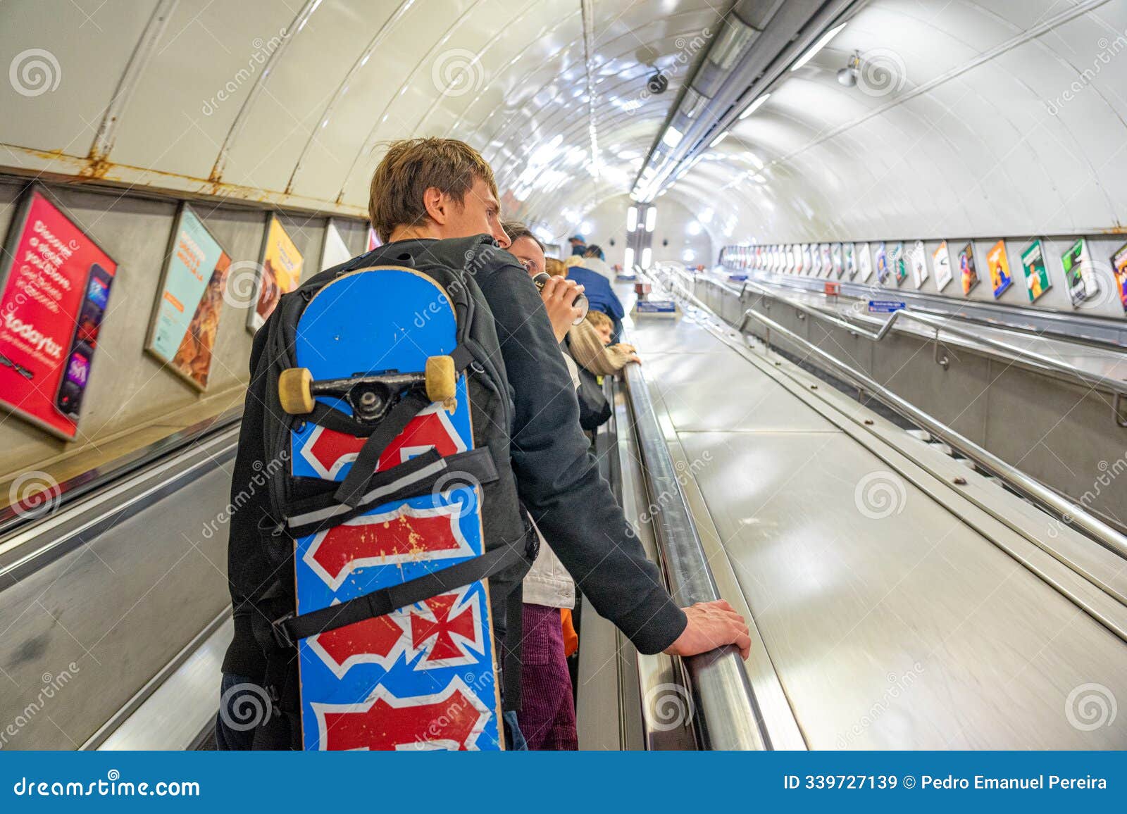 Passenger with Skateboard on His Back Going Up the Escalators Inside a ...