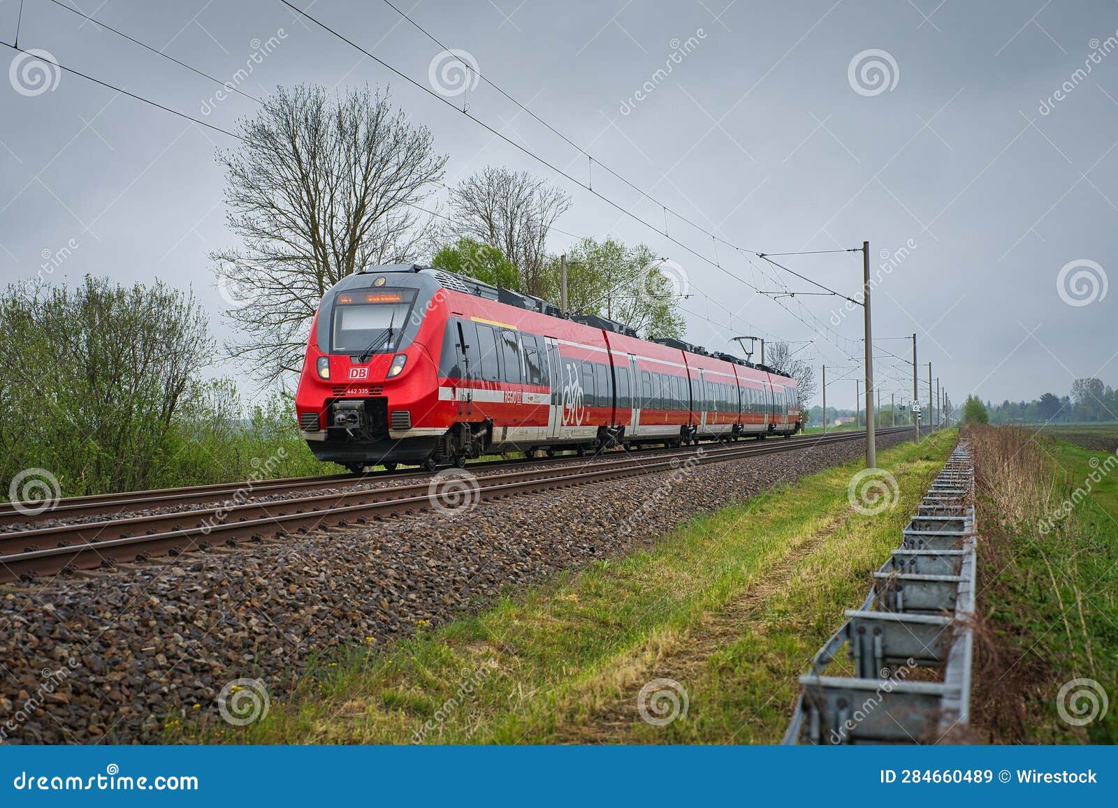 Passenger Train Chugging Along the Tracks in a Rural Setting with Tall ...