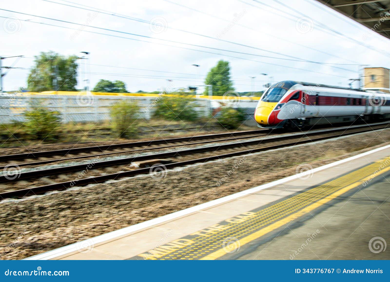 A Passing High Speed Passenger Train Flying Past a Train Station ...