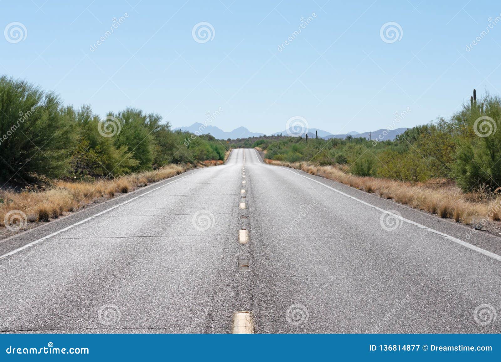 Paved Road Ahead through the Desert with Mountains in the Background ...