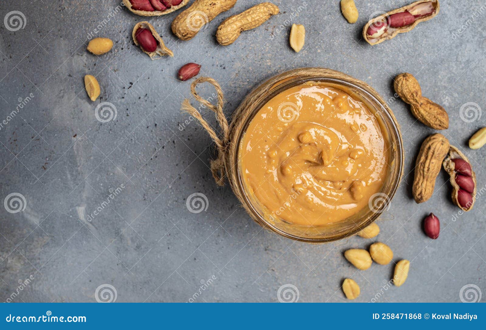 Peanut Paste in an Open Jar. Creamy Peanut Butter Peanuts Scattered ...