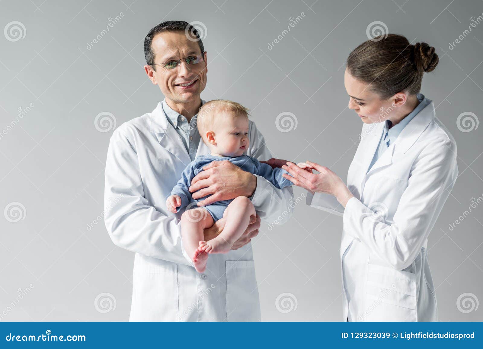 Two Pediatricians Are Taking Care Of Baby In Hospital. Little Girl Is ...