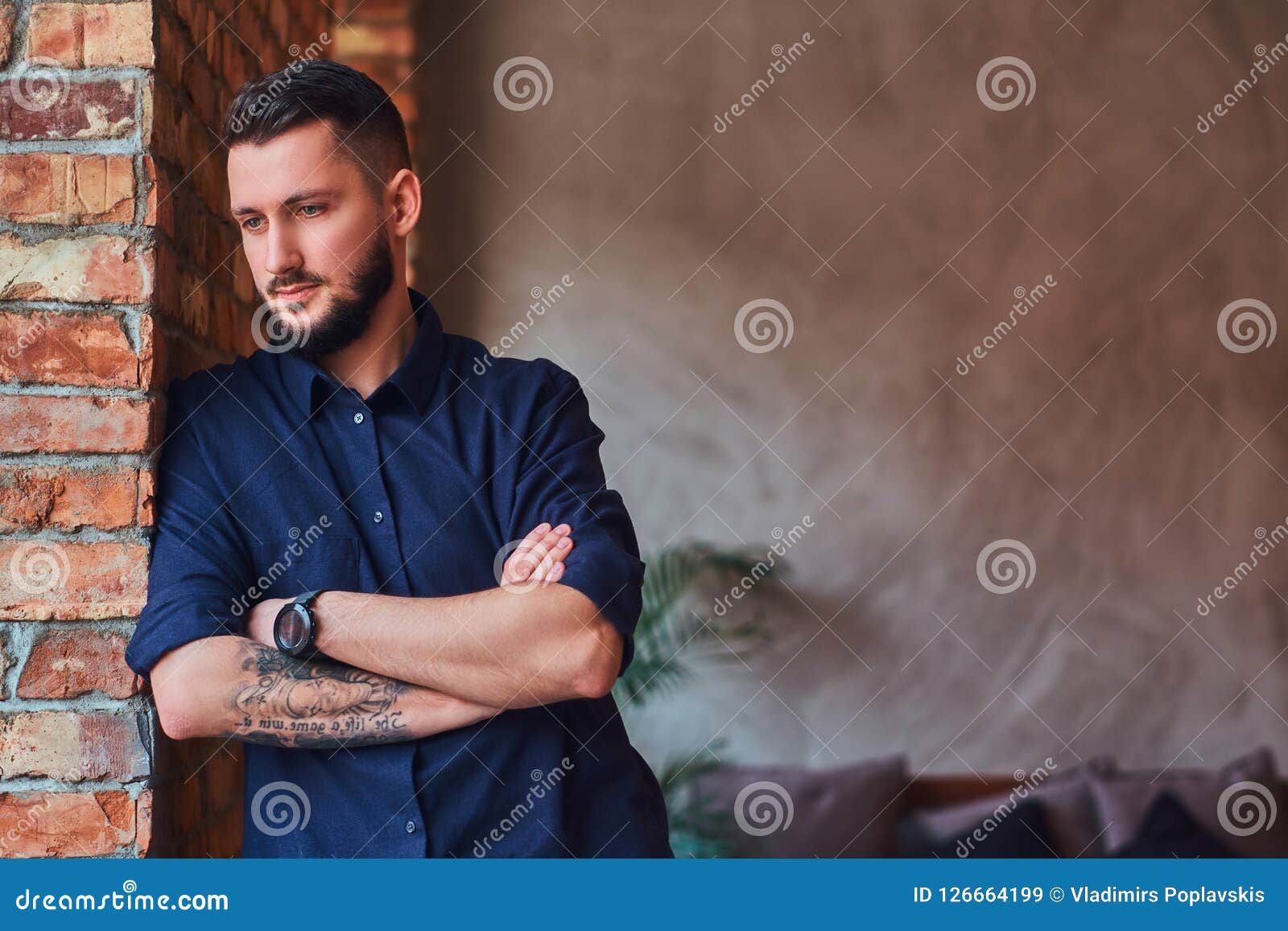 Pensive Bearded Man Standing With Crossed Arms Near Desktop In The