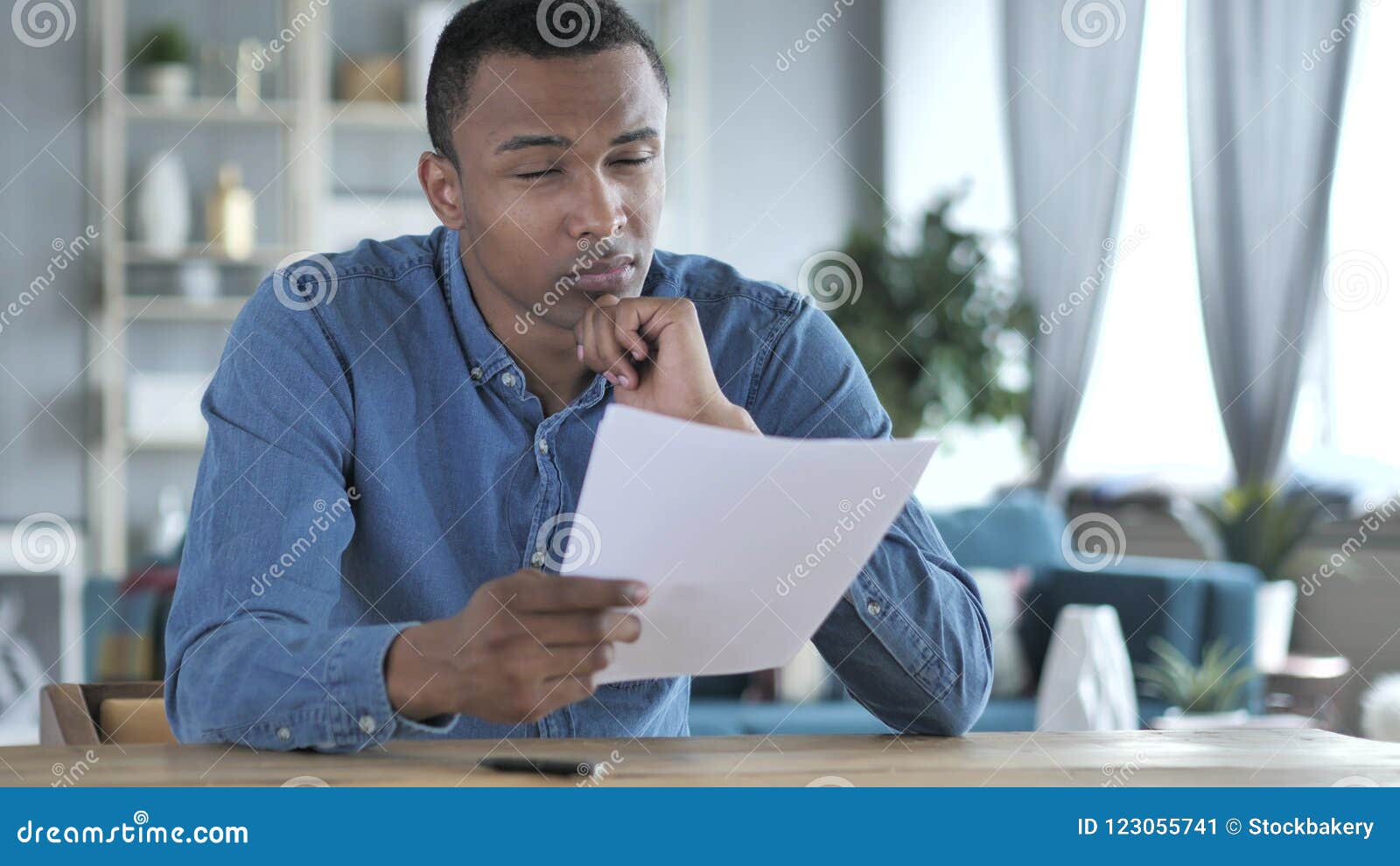 Pensive Young African Man Reading and Writing on Documents, Paperwork ...