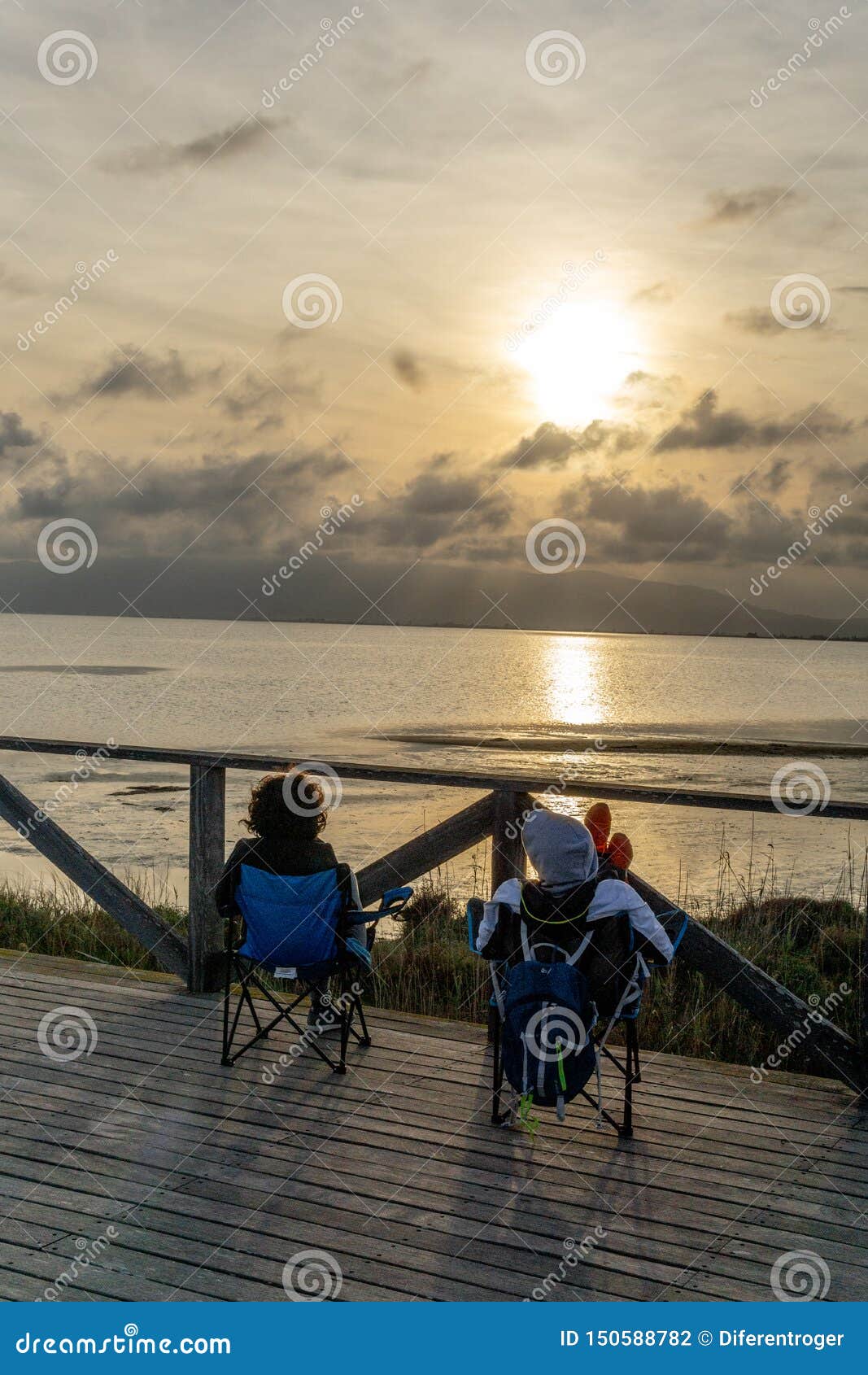An Unrecognizable Couple Sitting Contemplating the Sunset on the Sea ...