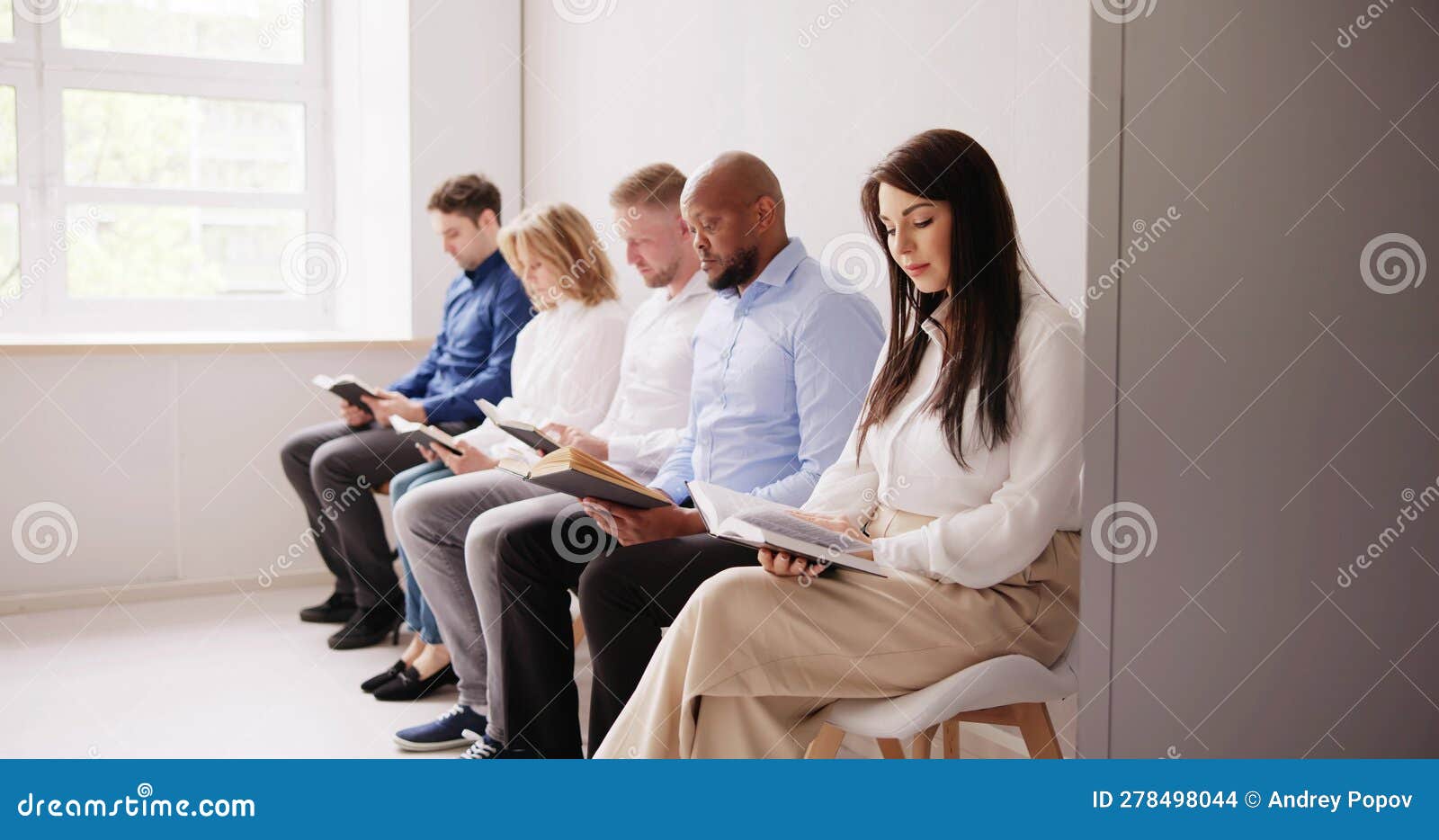 People Sitting in a Row Reading Stock Photo - Image of floor, people ...