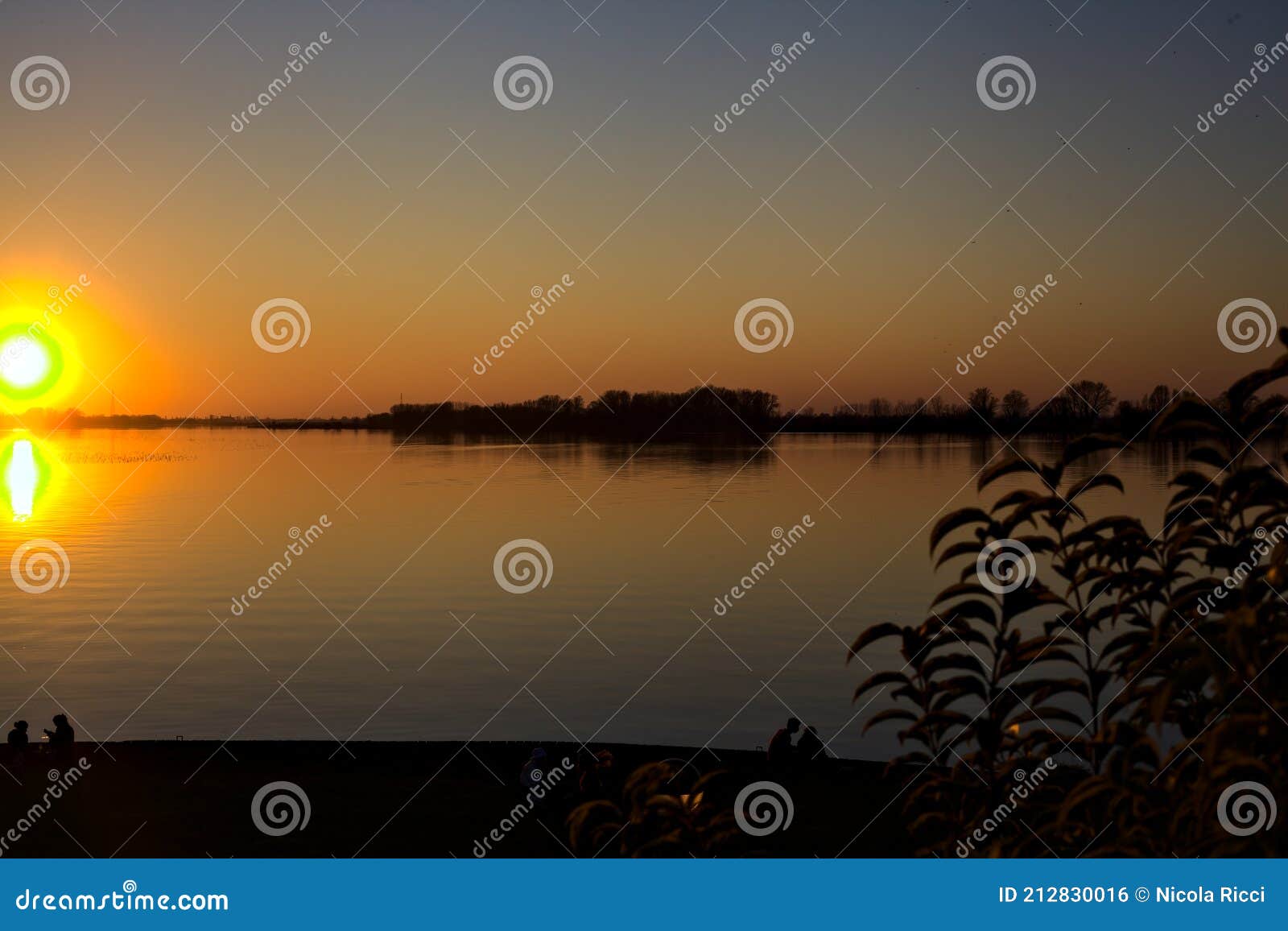 People Sitting by the Shore of a River at Sunset Stock Photo - Image of ...