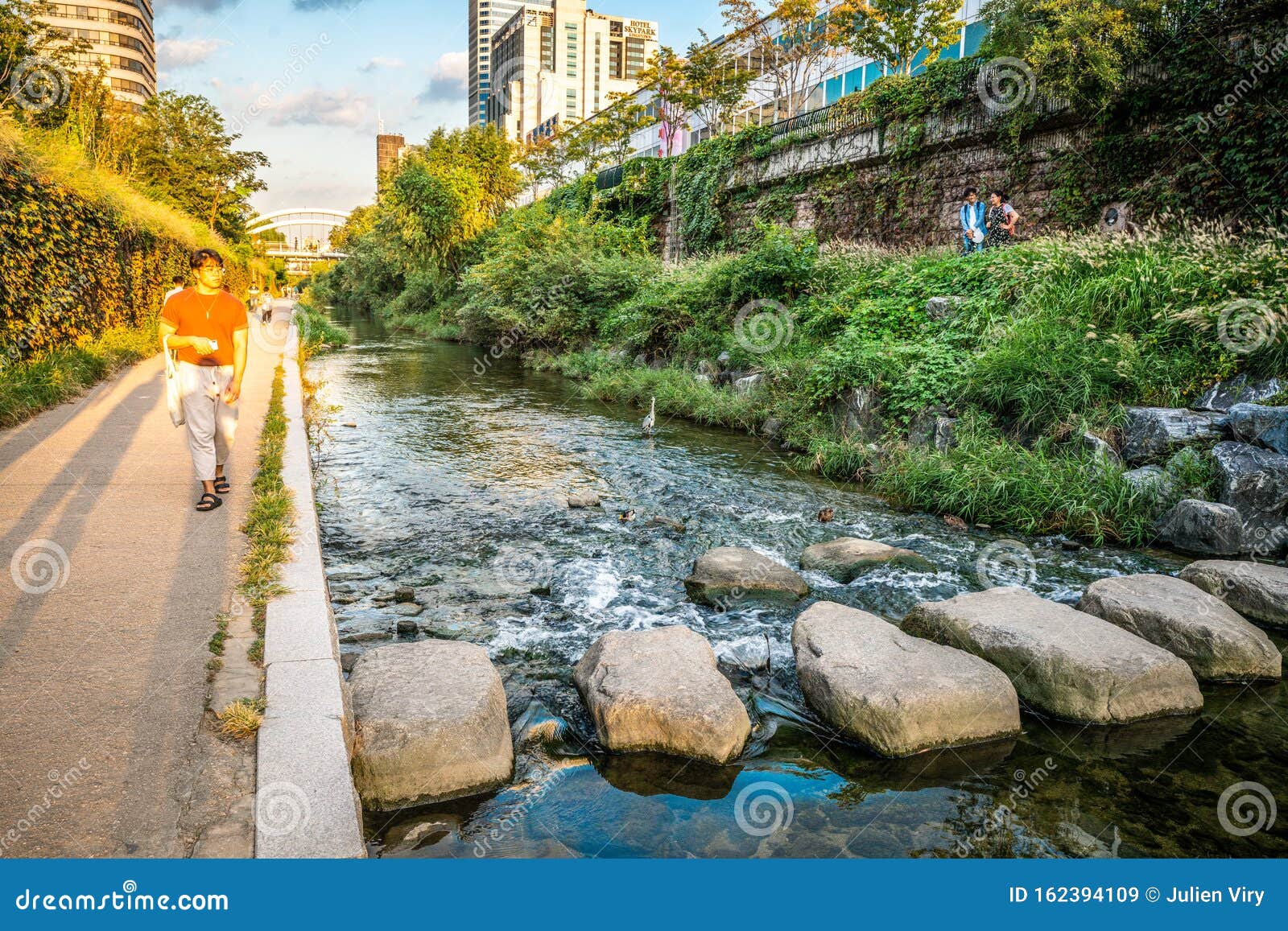 People Walking Along Cheonggyecheon Stream at Sunset with Dramatic ... People Walking Along Cheonggyecheon Stream at Sunset with Dramatic ...