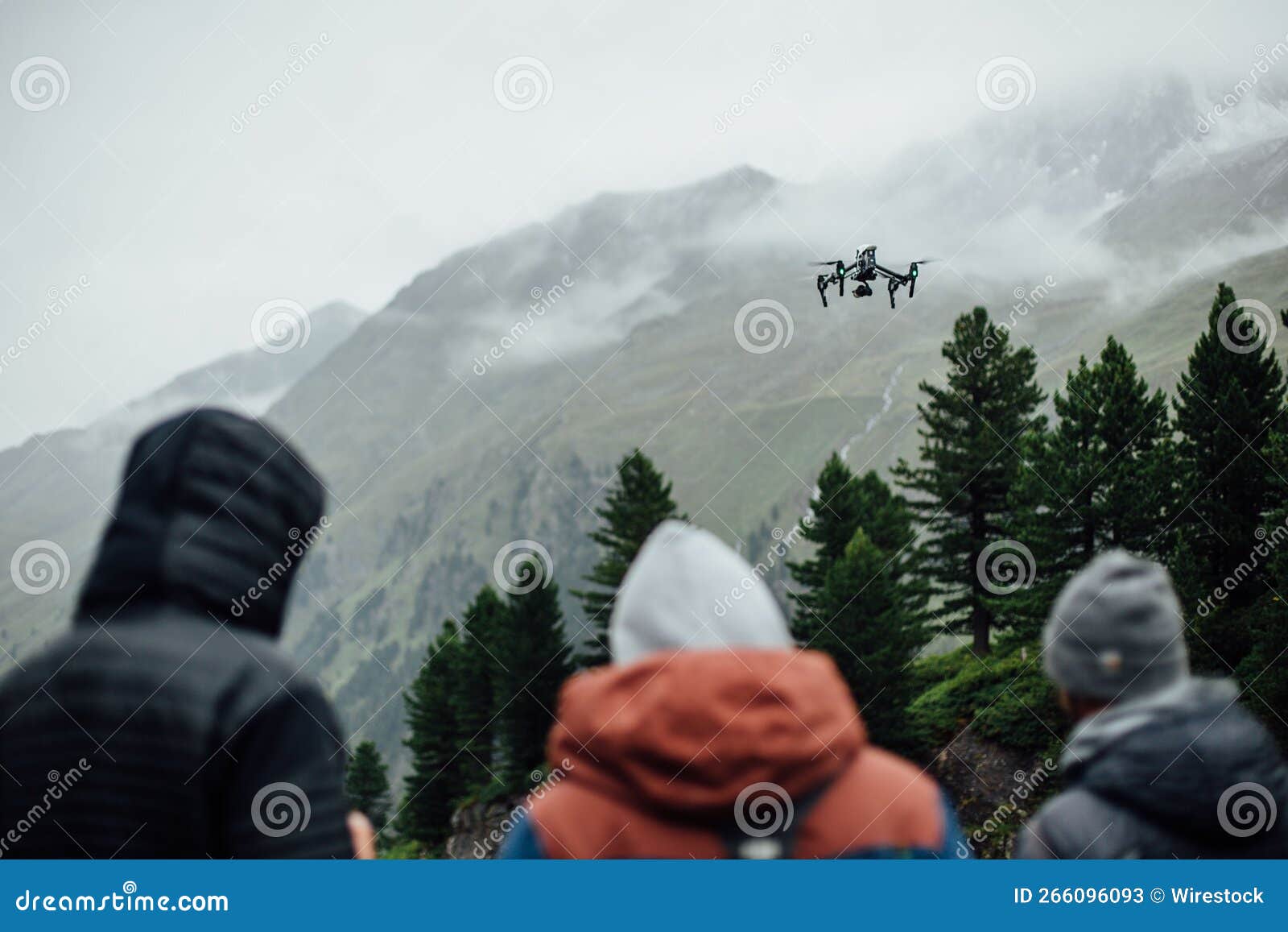 People Watching the Drone Flying Over the Trees and Mountains Covered ...