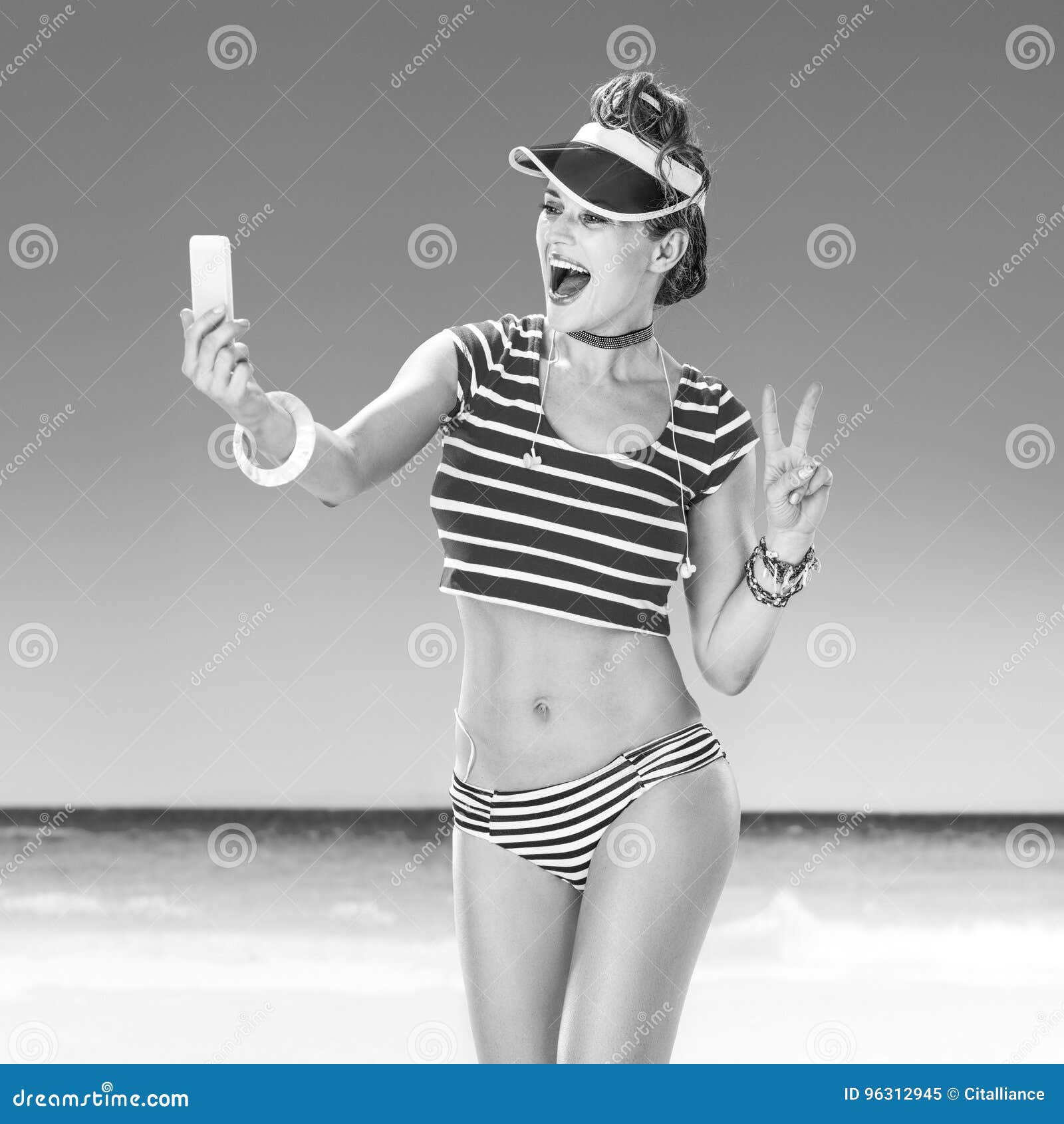 Woman On Beach Taking Selfie With Cellphone And Showing Victory Stock