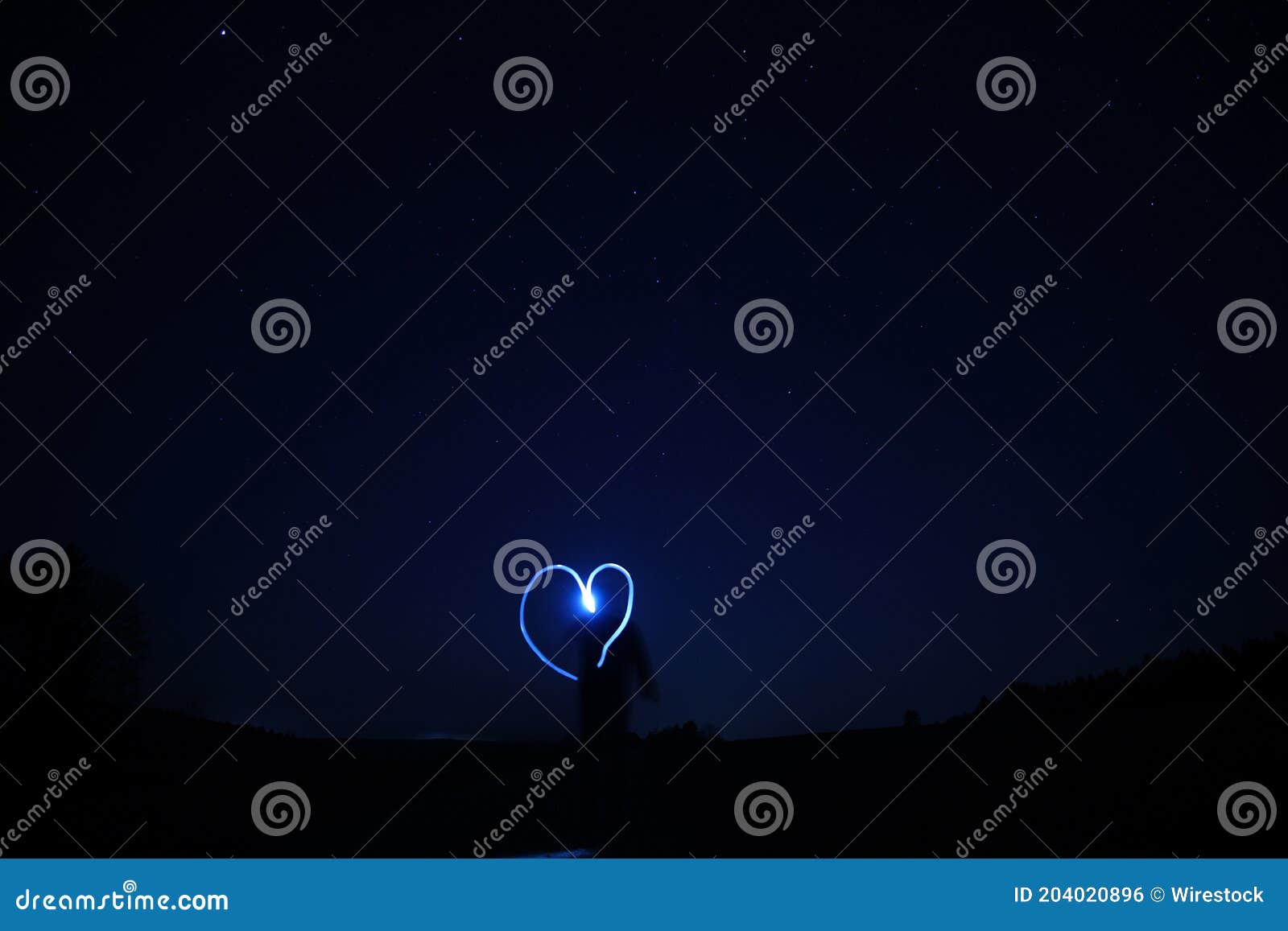 Person Drawing a Heart Shape with Light with Long Exposure Under a ...