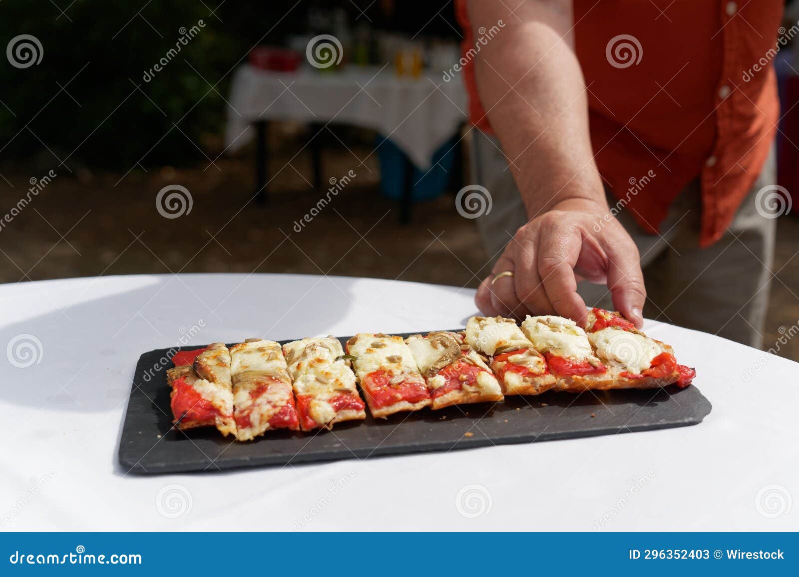 A Person Grabbing Up Some Pizza on a Rectangular Tray on a Table Stock ...