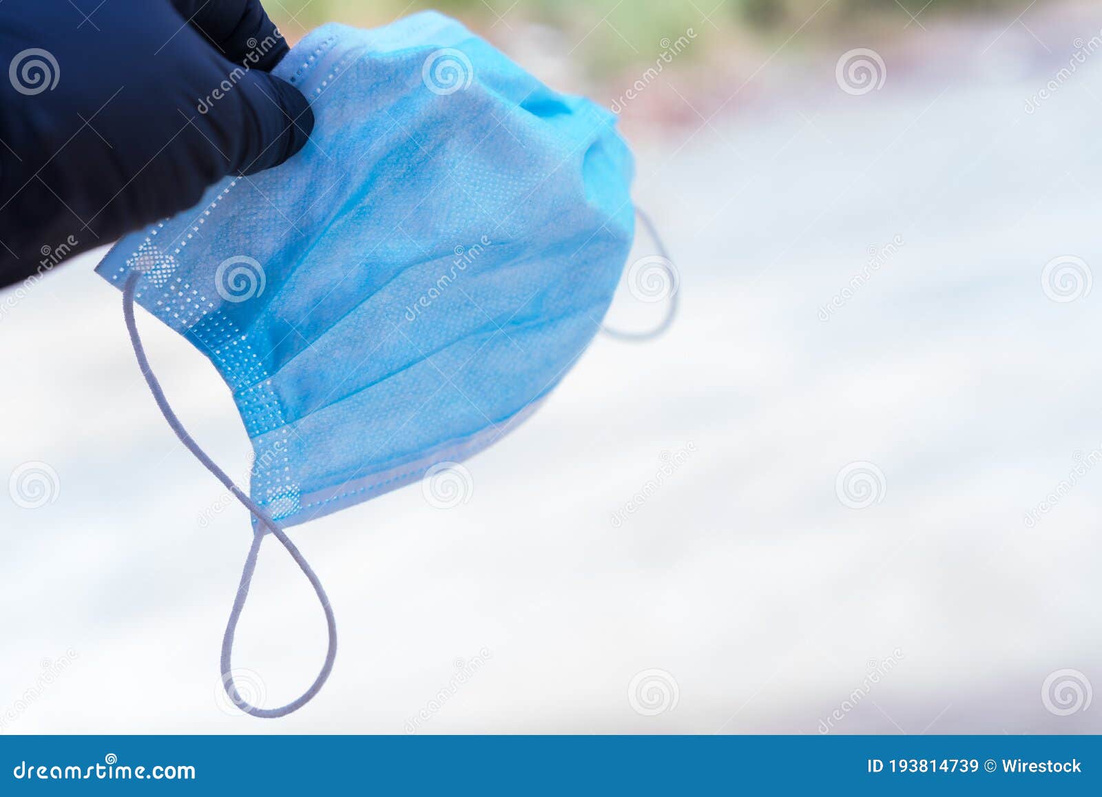 Person Holding a Blue Protective Face Mask with a Blurry Background ...